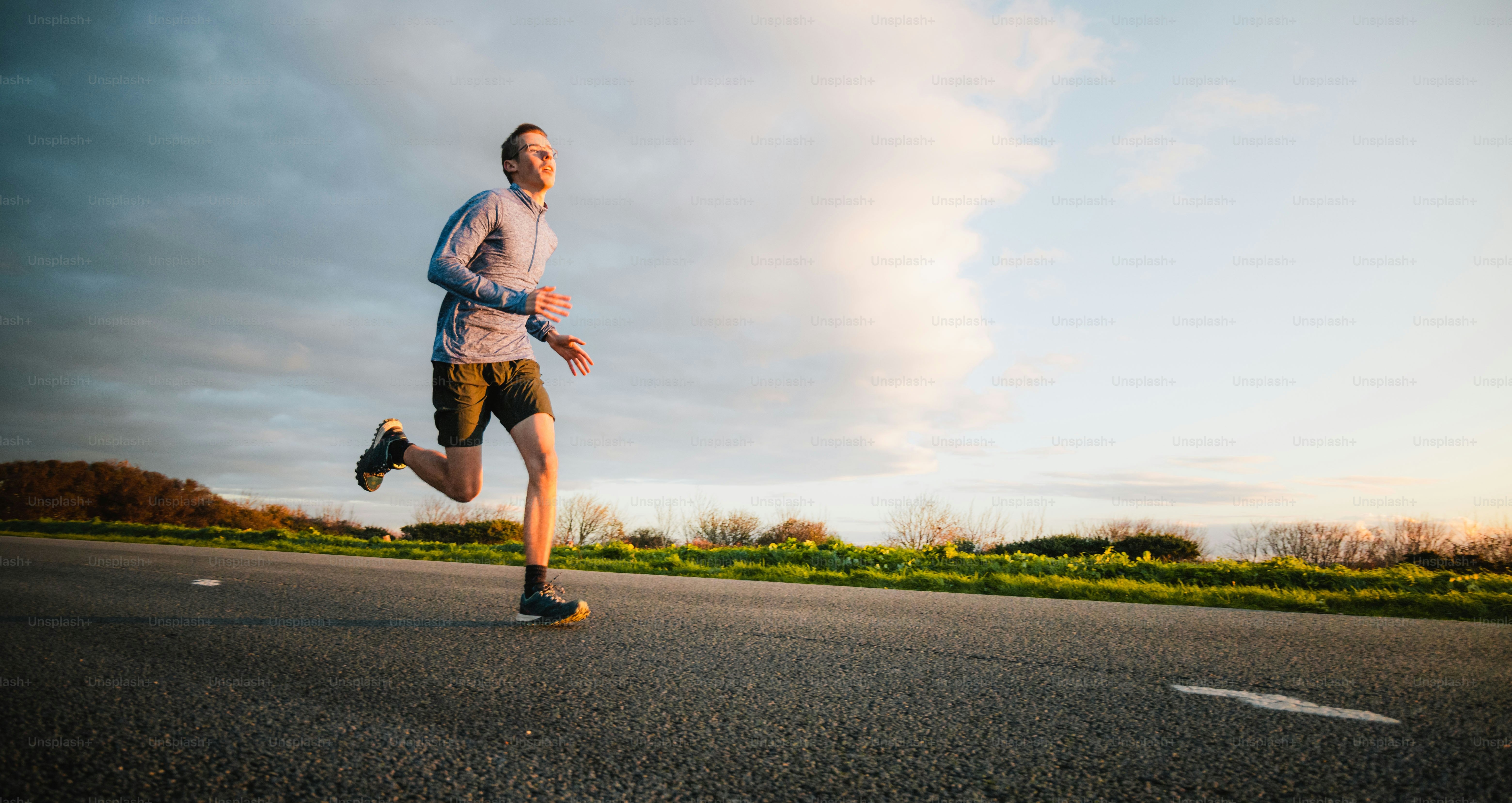 A man running down a road in the middle of the day photo – Running ...