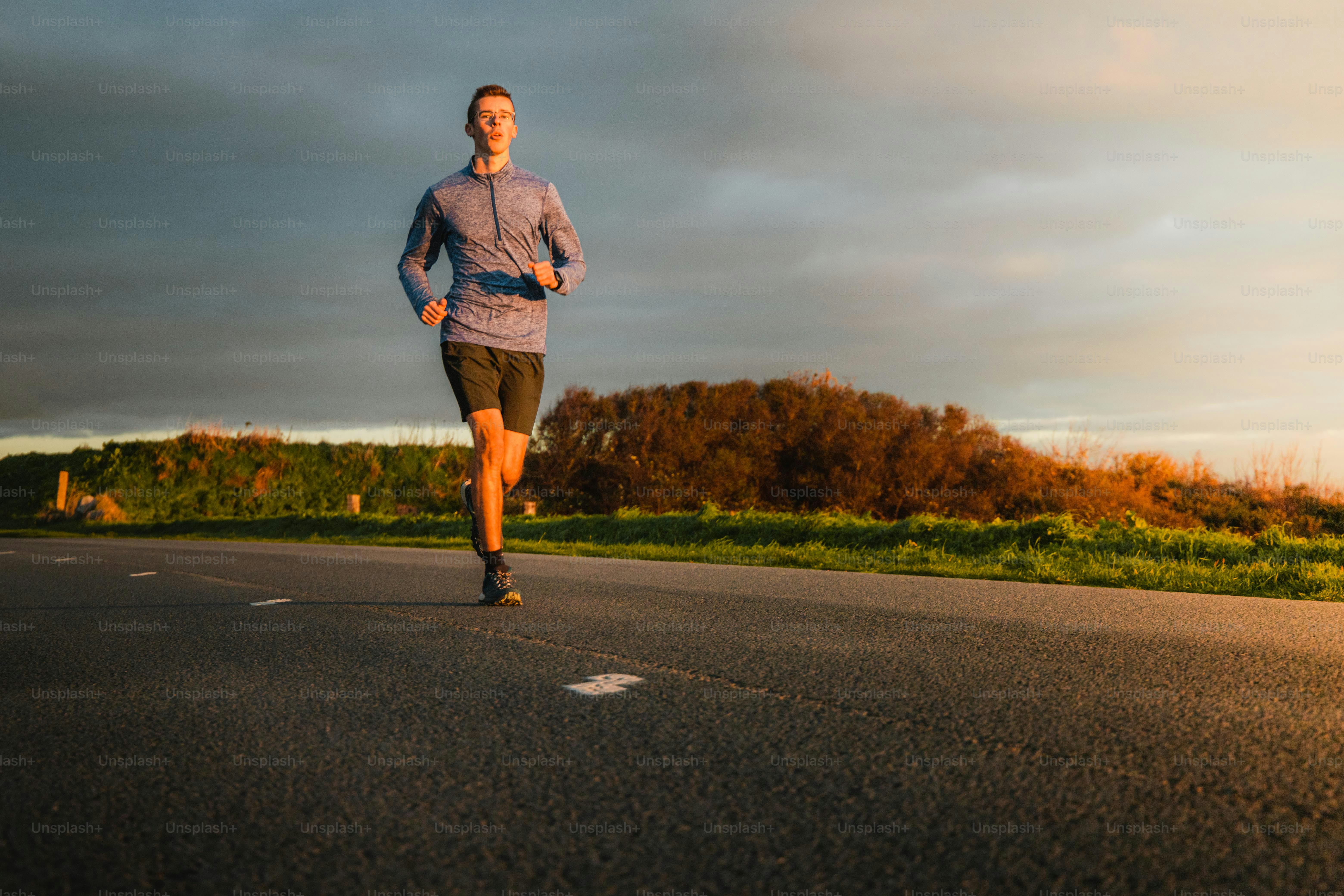 A man running down a road at sunset photo – Running Image on Unsplash