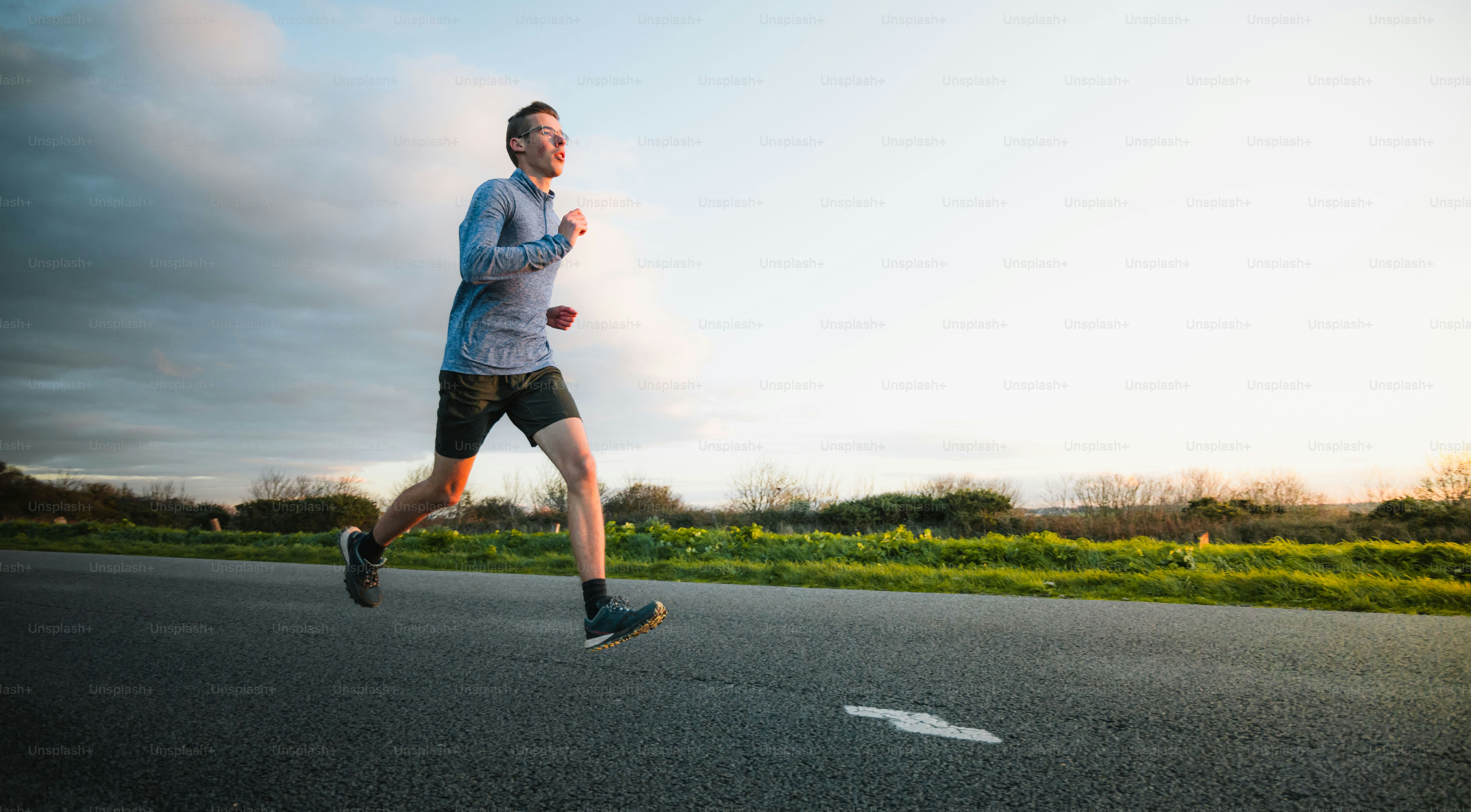 A man running down a road in the middle of the day photo – Runner Image ...