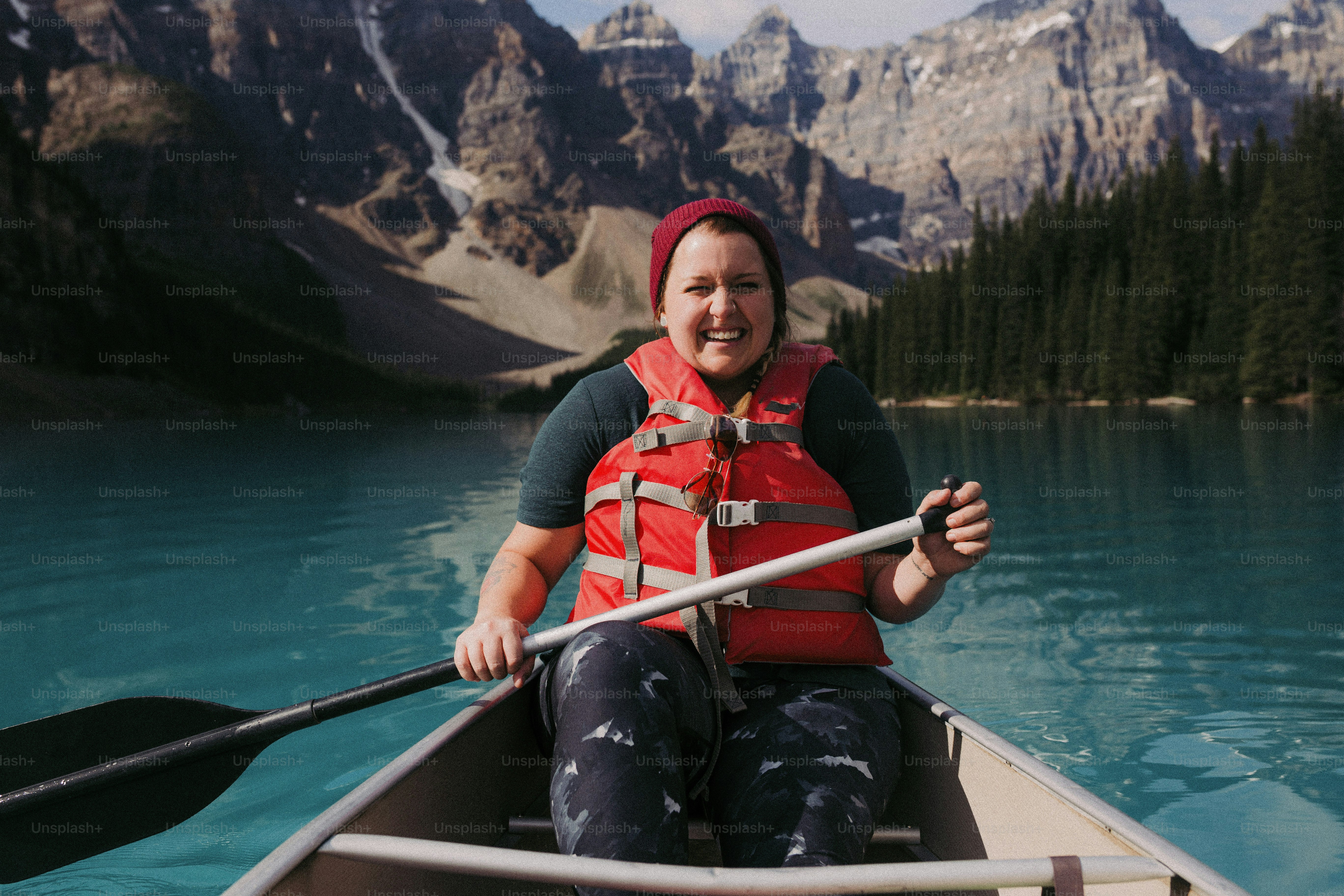 A woman in a red life jacket paddling a canoe photo – One person Image ...