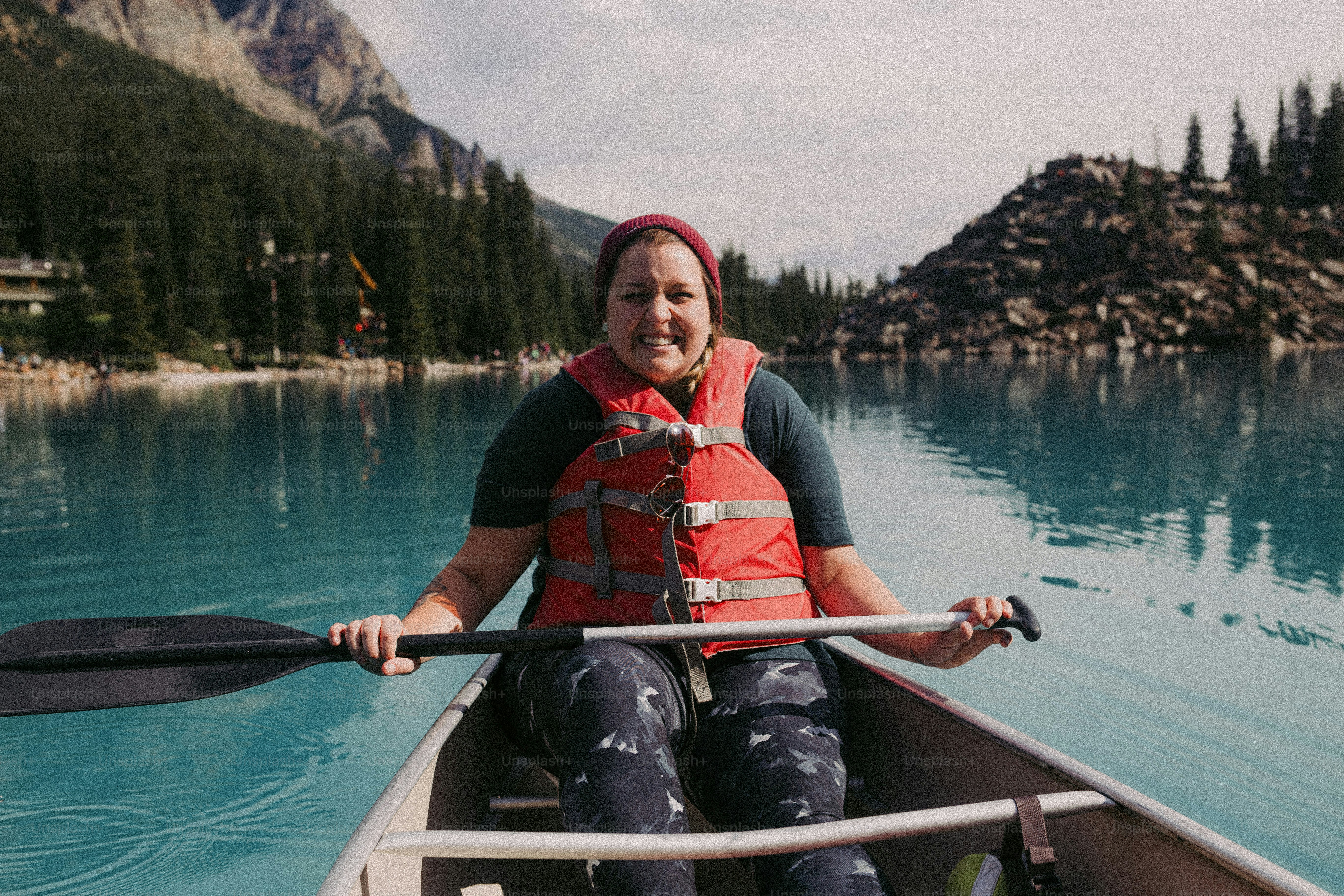 A woman in a red life jacket paddling a canoe photo – Life jacket Image ...