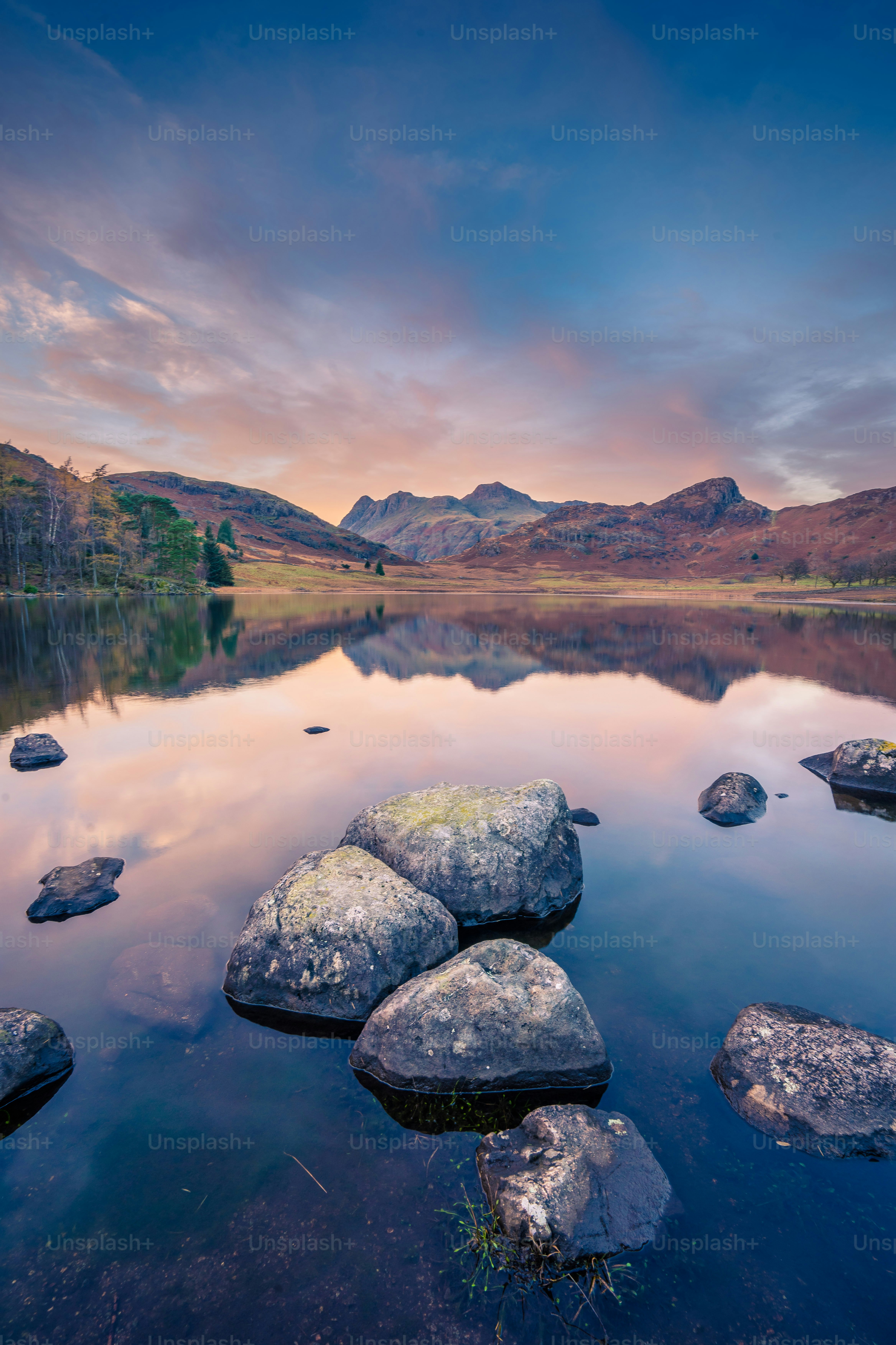 A lake with rocks in the water and mountains in the background photo ...