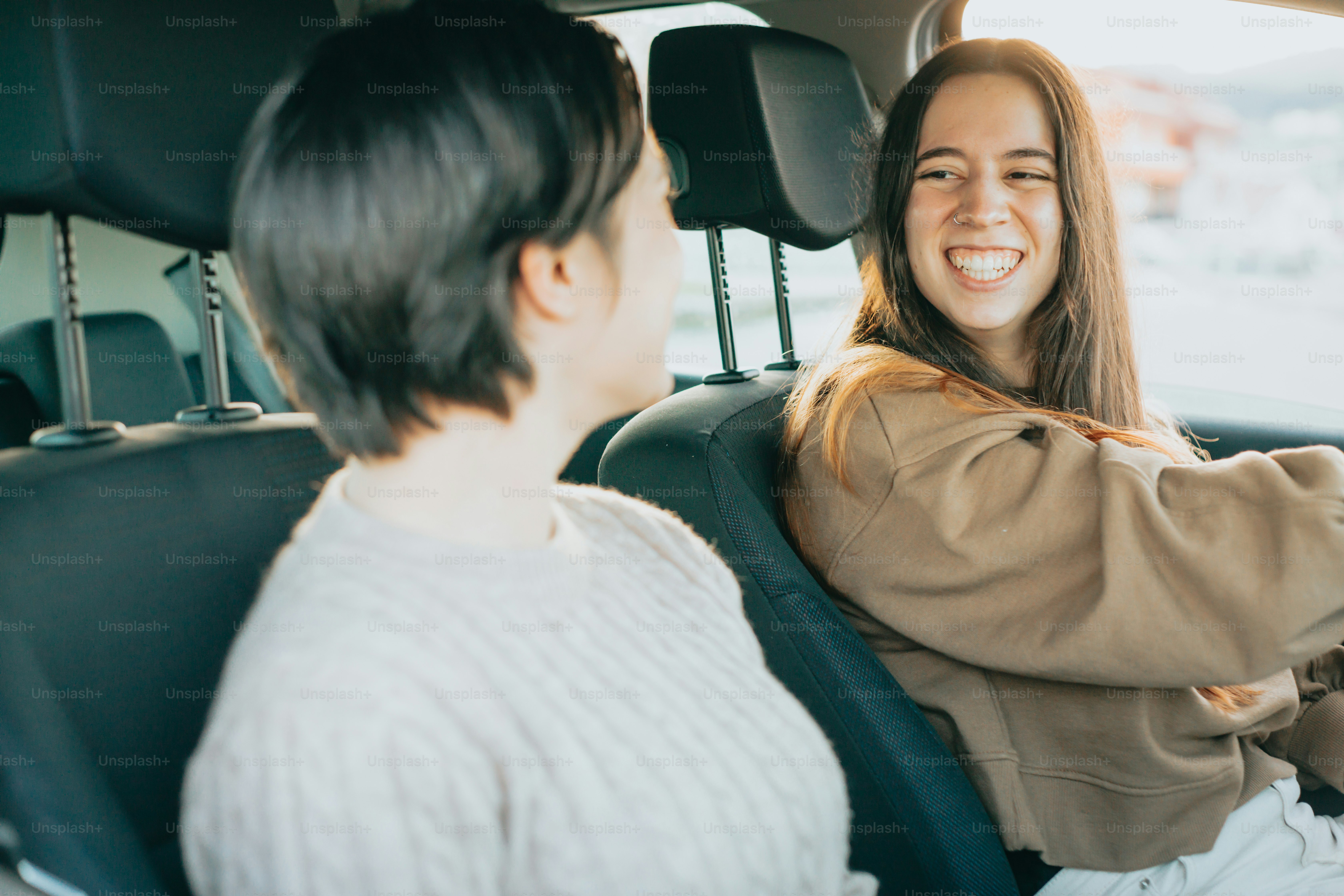 A woman sitting in the back seat of a car talking to another woman ...