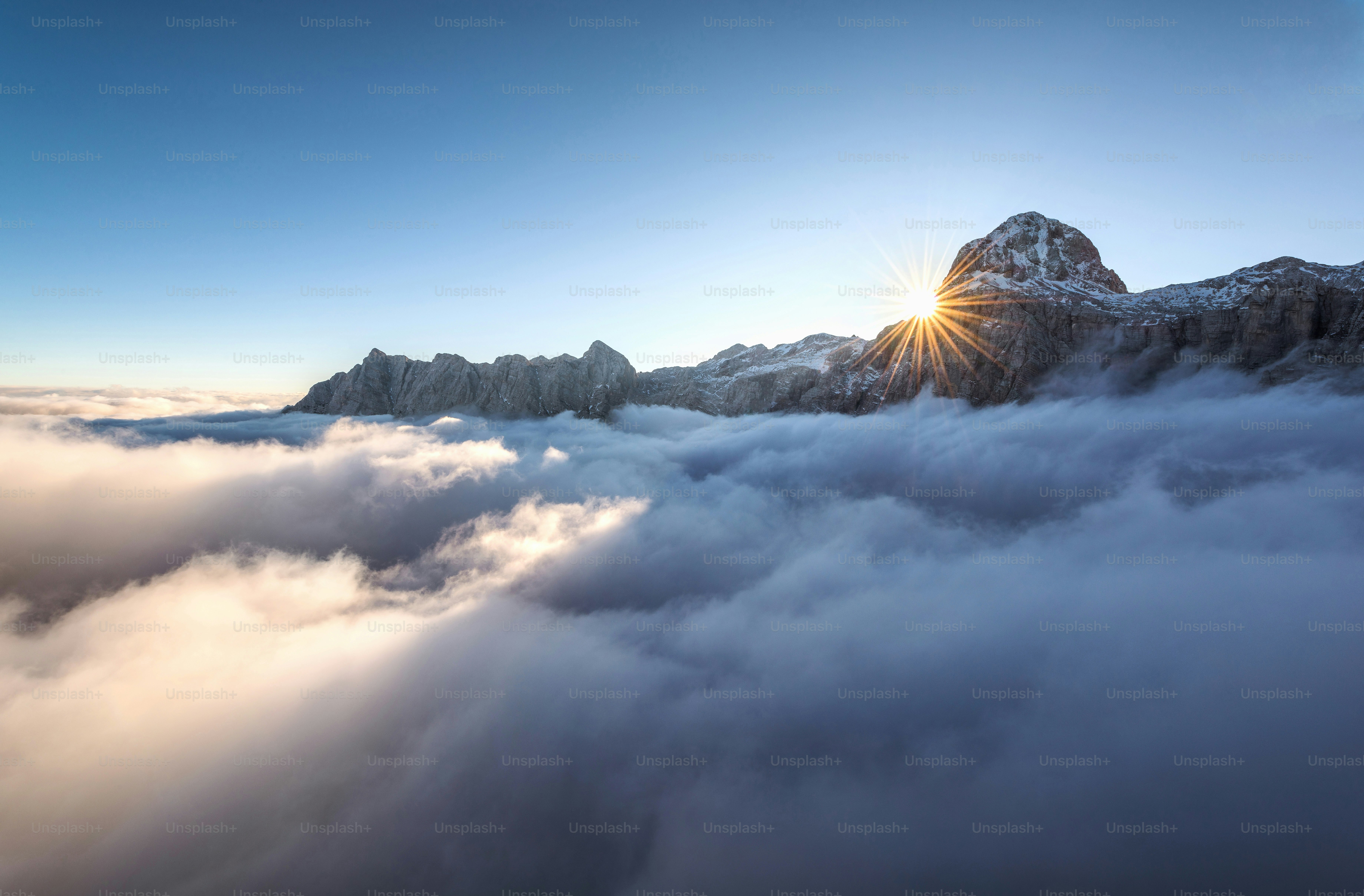 The sun shines brightly above the clouds on top of a mountain photo ...