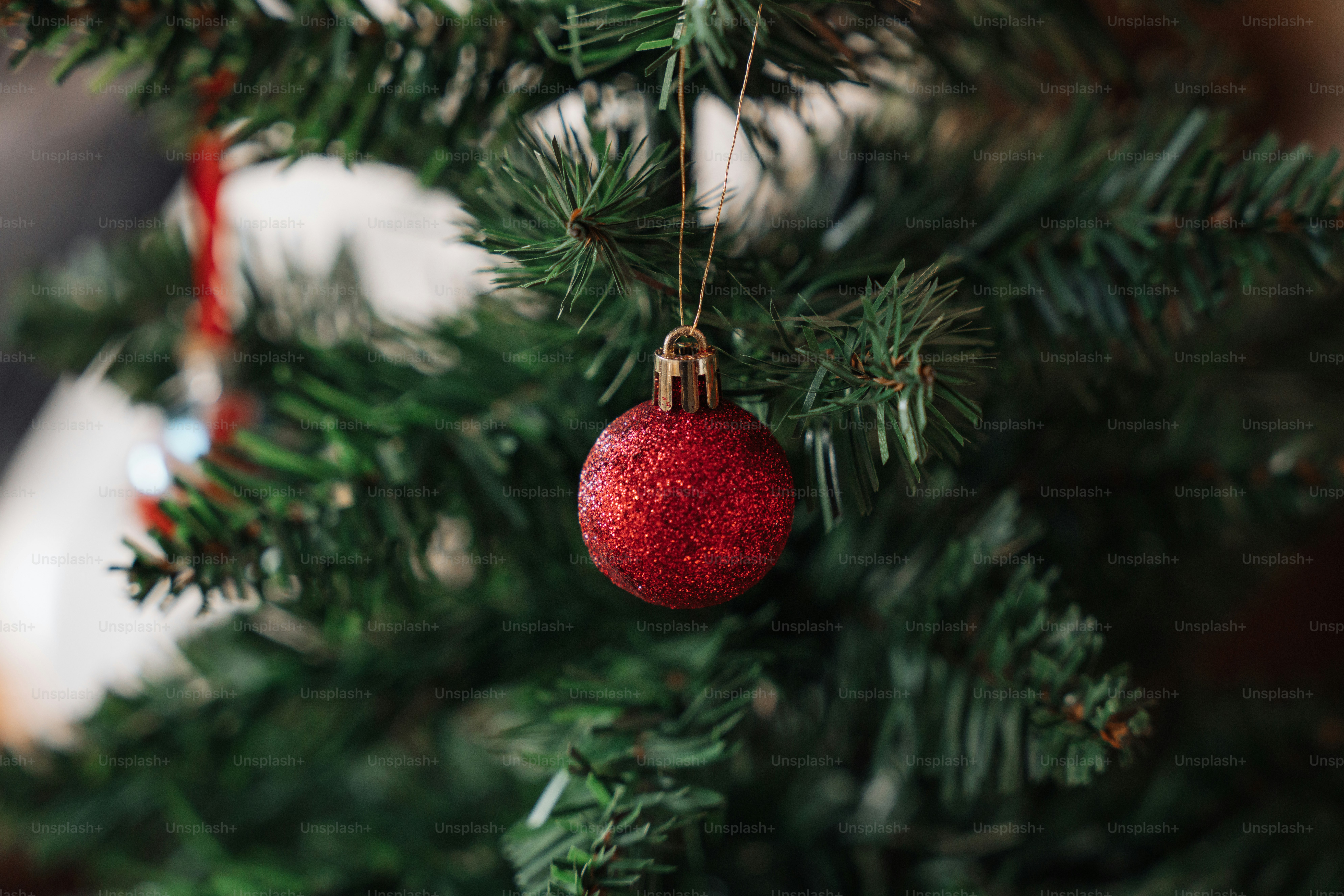 A red ornament hanging from a christmas tree photo – Christmas tree ...