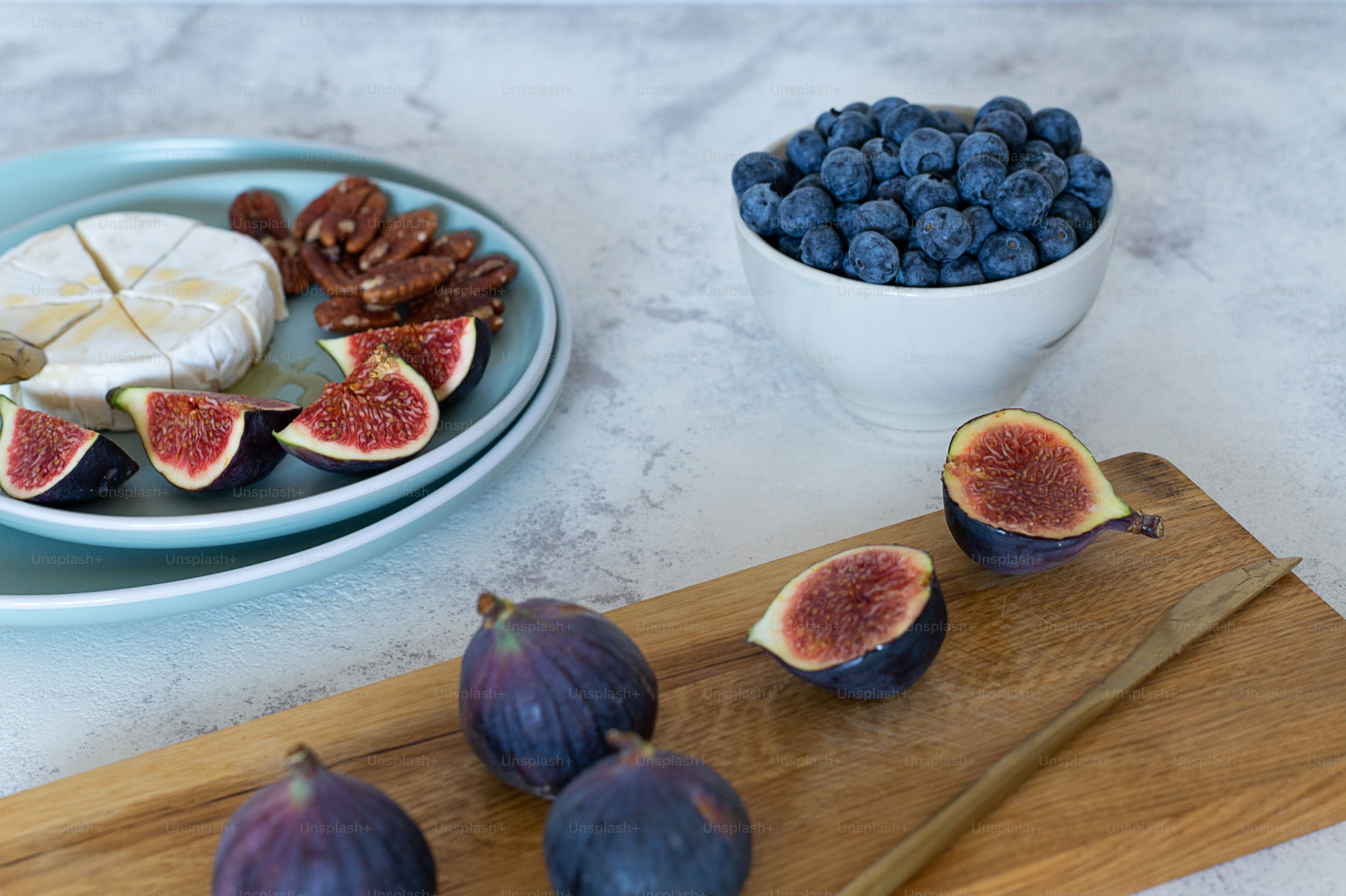 Figs, blueberries, cheese and nuts on a cutting board photo – Fruit ...