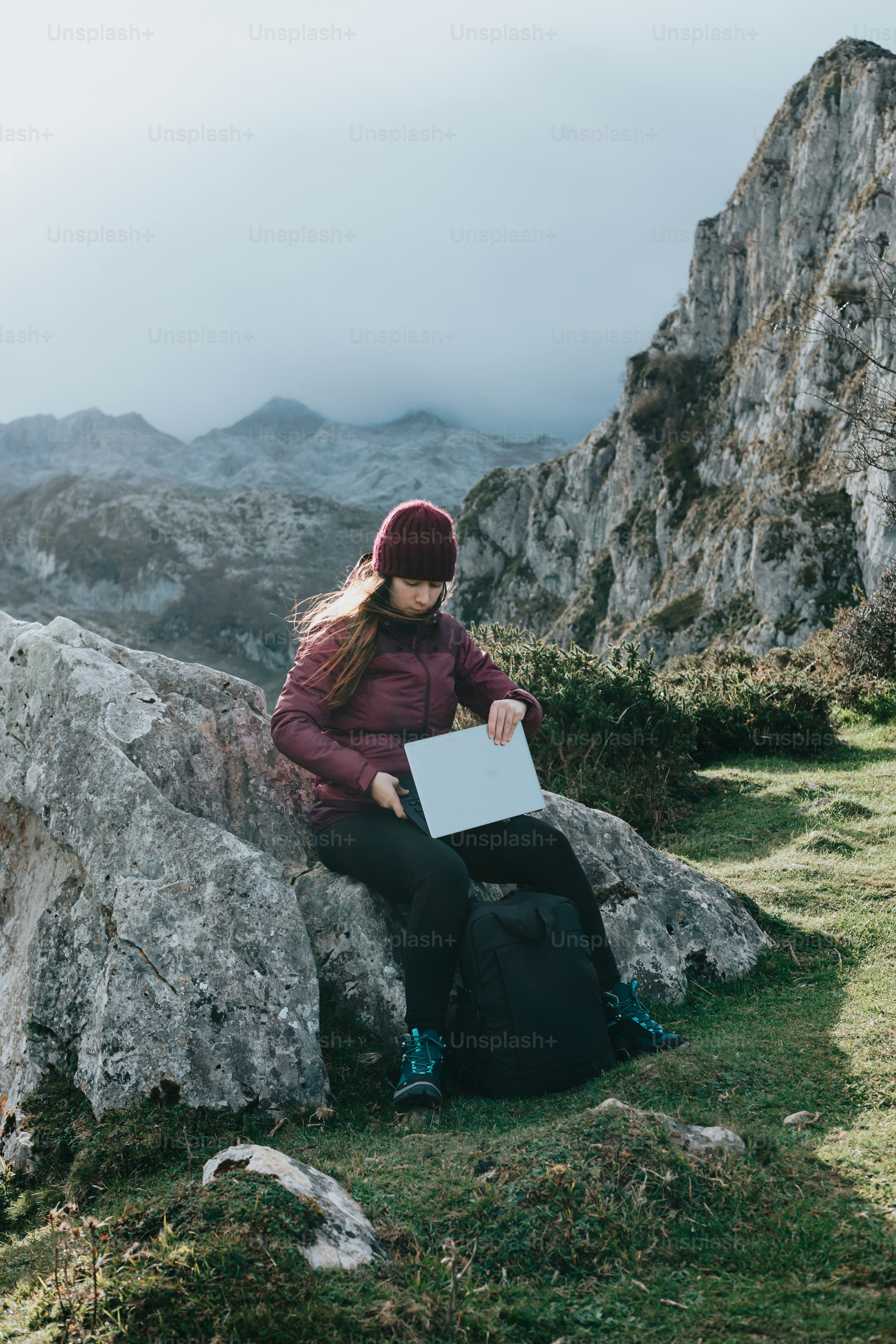Una mujer sentada en una roca con una computadora portátil foto ...
