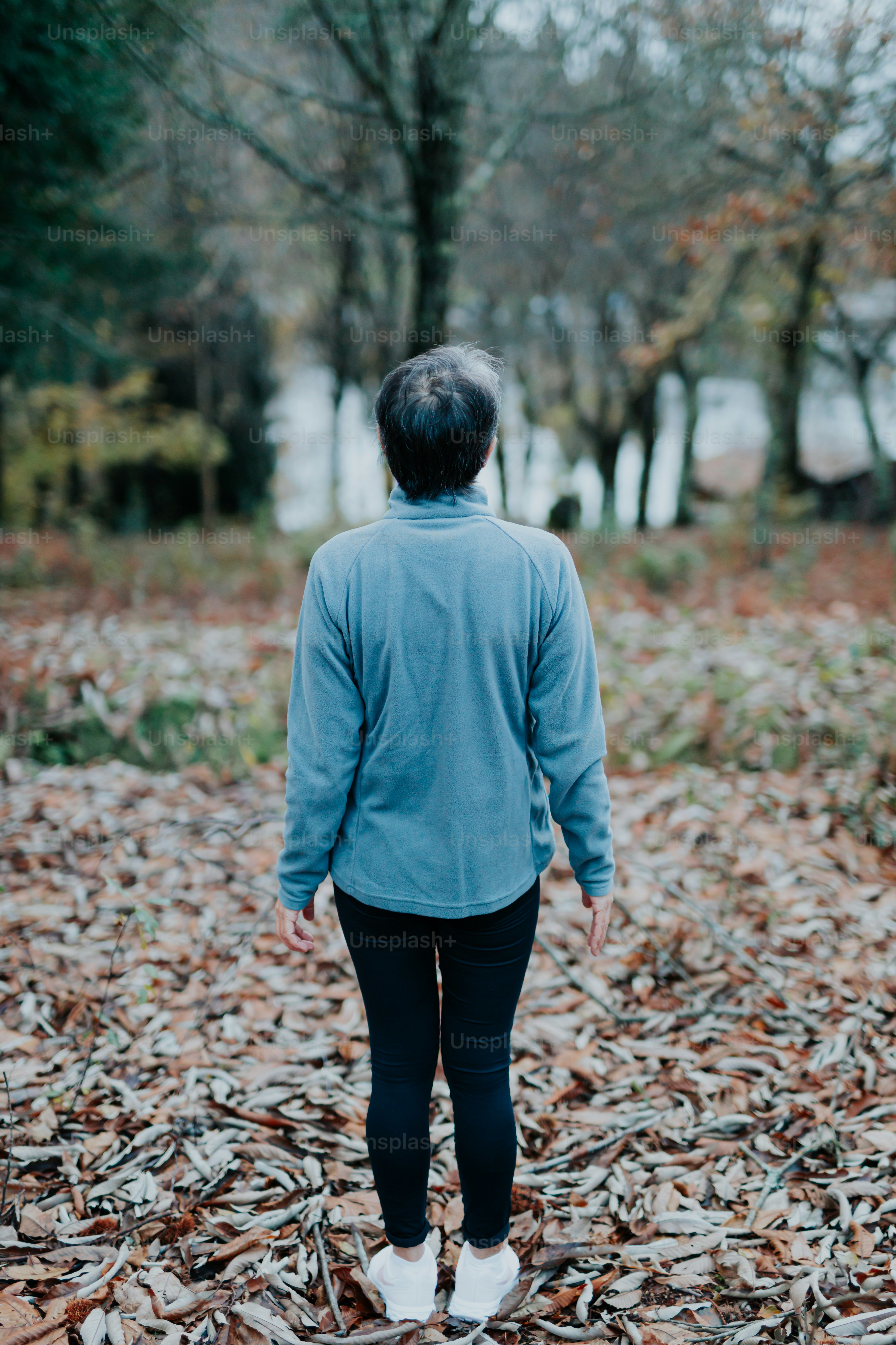 A woman walking through a leaf covered forest photo – Excising Image on ...
