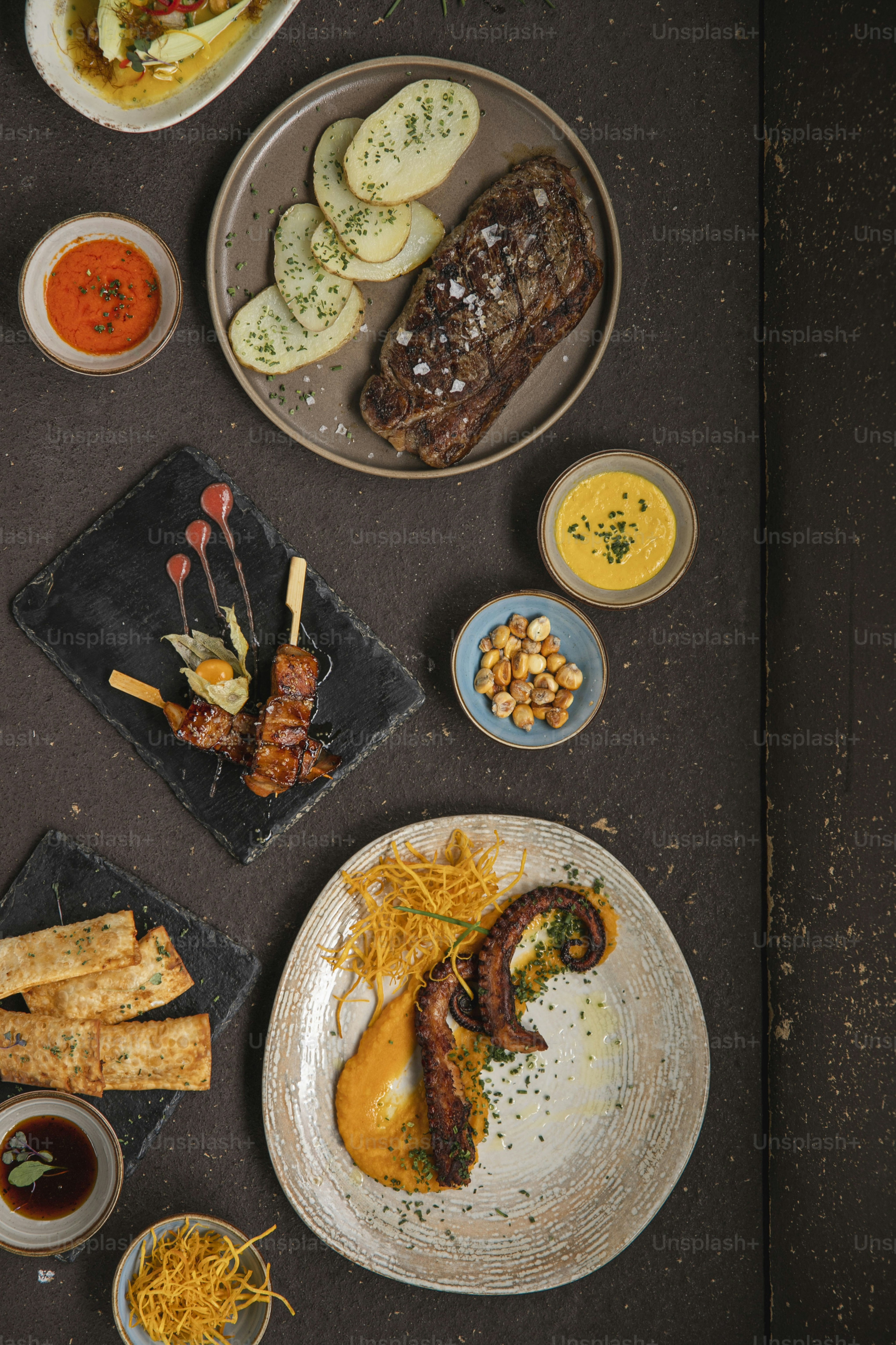A table topped with plates of food and condiments photo – Steak Image ...