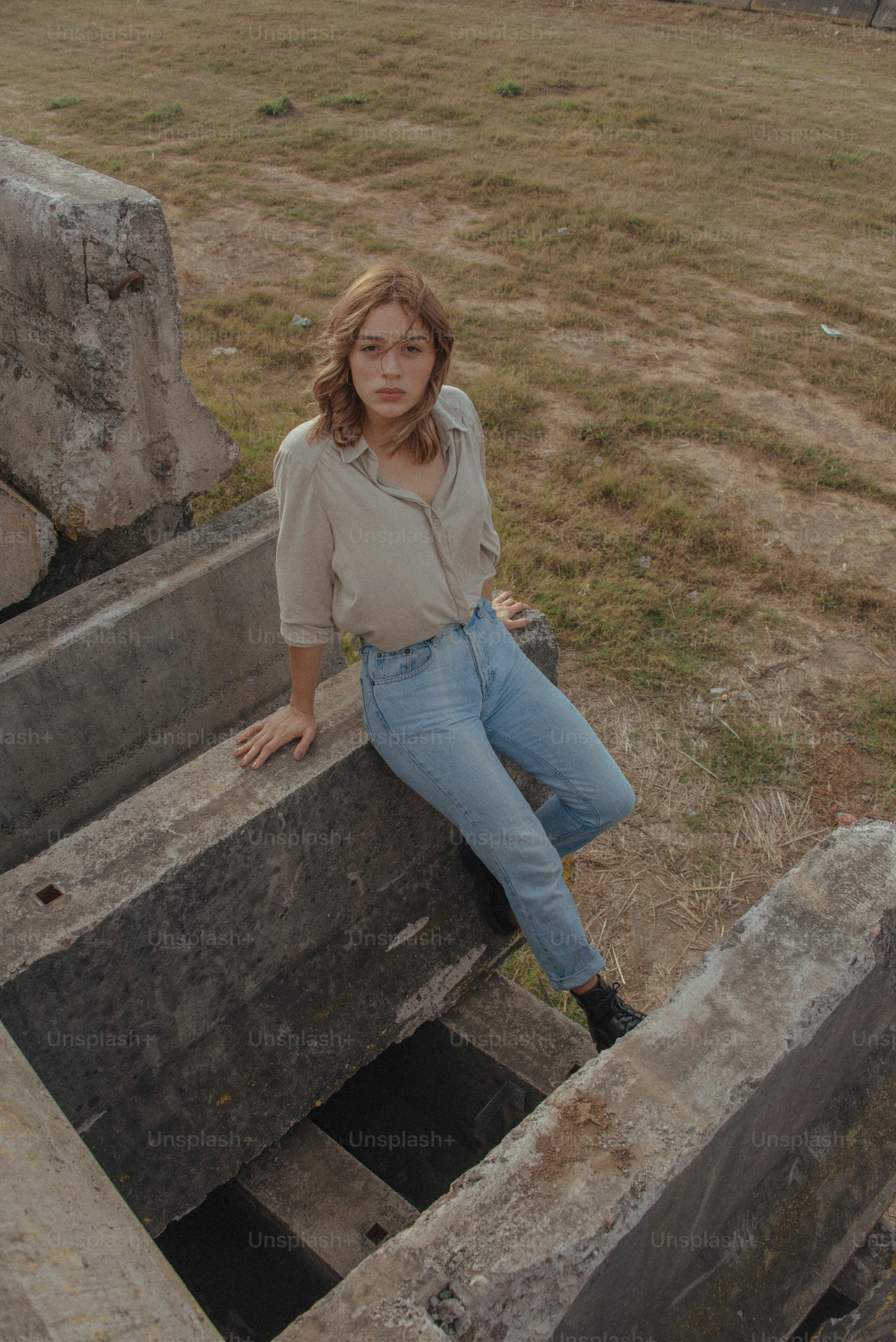 Foto Una persona sentada en un muro de piedra – Femenino Imagen en Unsplash