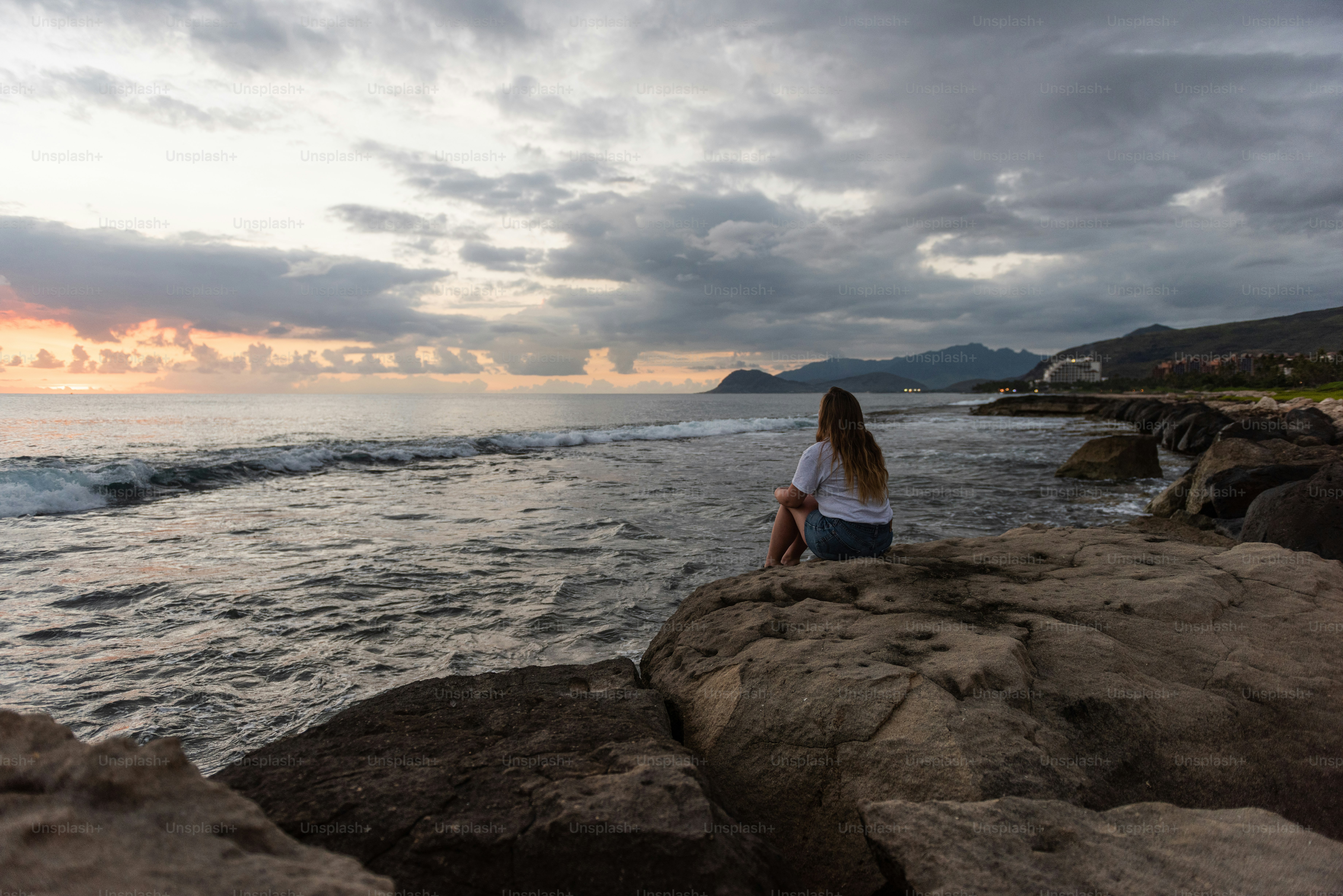 A person sitting on a rock by the water photo – Person Image on Unsplash