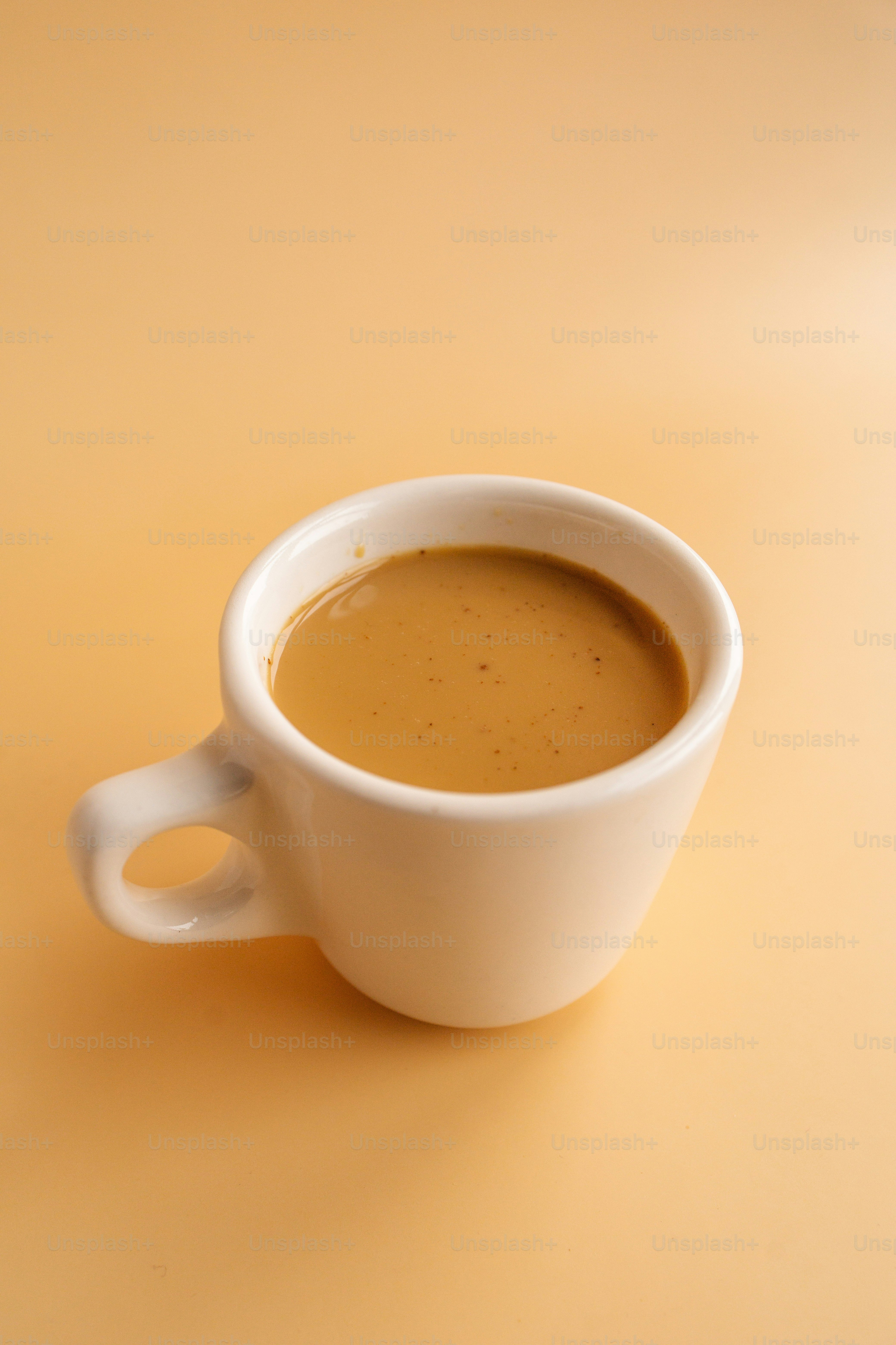 A white cup with a brown liquid photo – Minimal coffee Image on Unsplash
