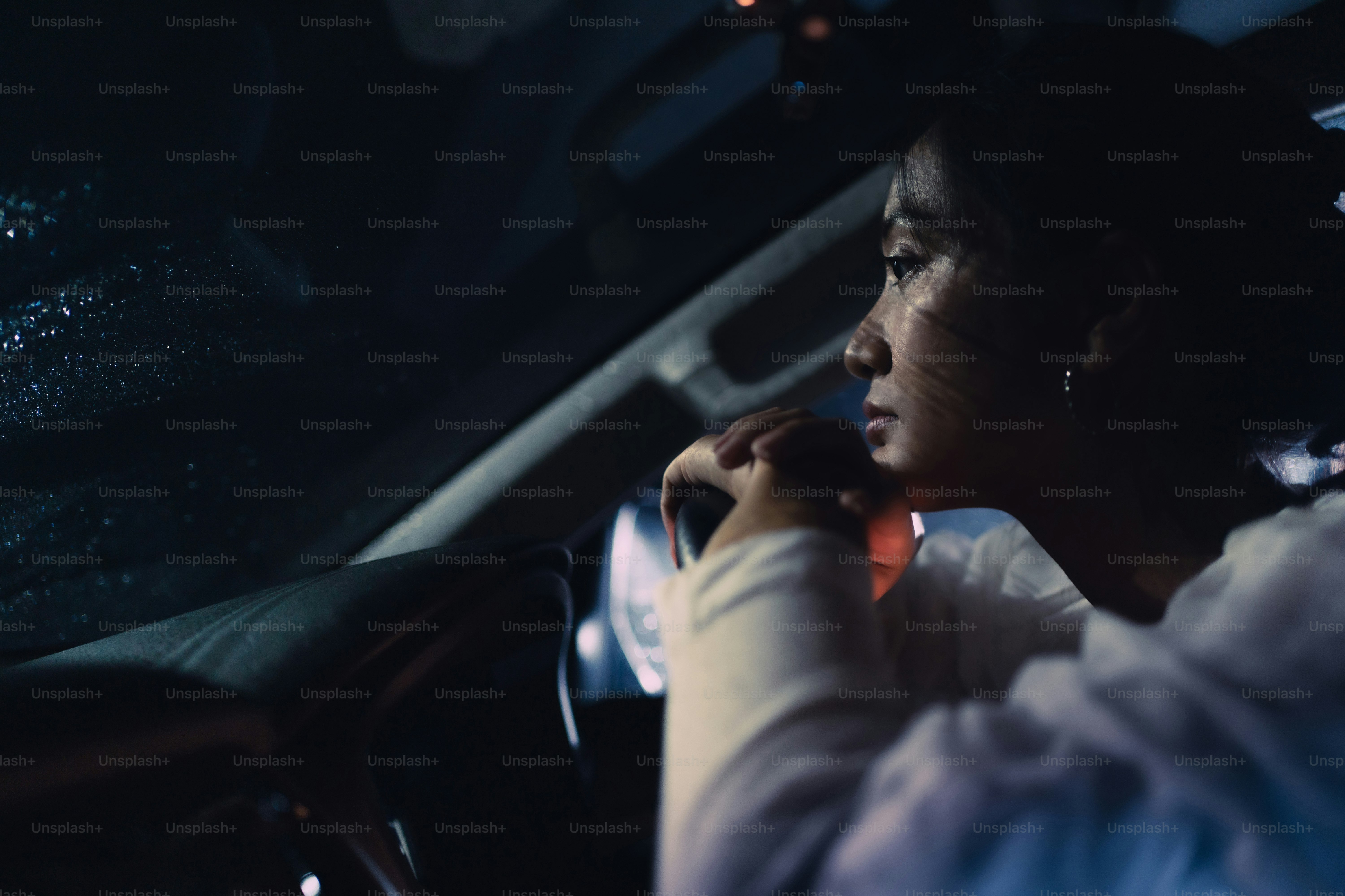 Asian woman is driving alone at night. It's raining. She is lonely ...