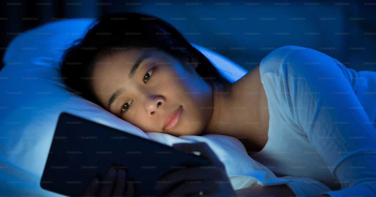 아시아 여성들은 밤에 자기 전에 침대에서 태블릿을 사용하고 있습니다 모바일 중독자 개념입니다 사진 Unsplash의