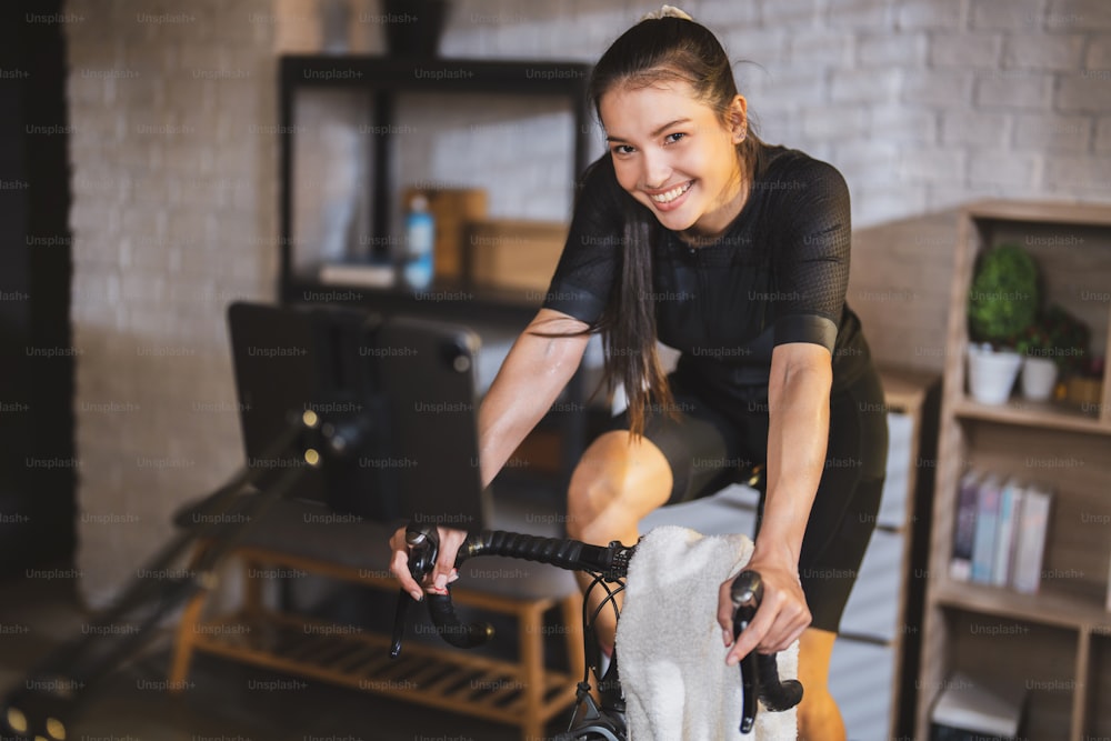 Foto Ciclista asiática. Ella está haciendo ejercicio en la casa ... Foto Ciclista asiática. Ella está haciendo ejercicio en la casa ...