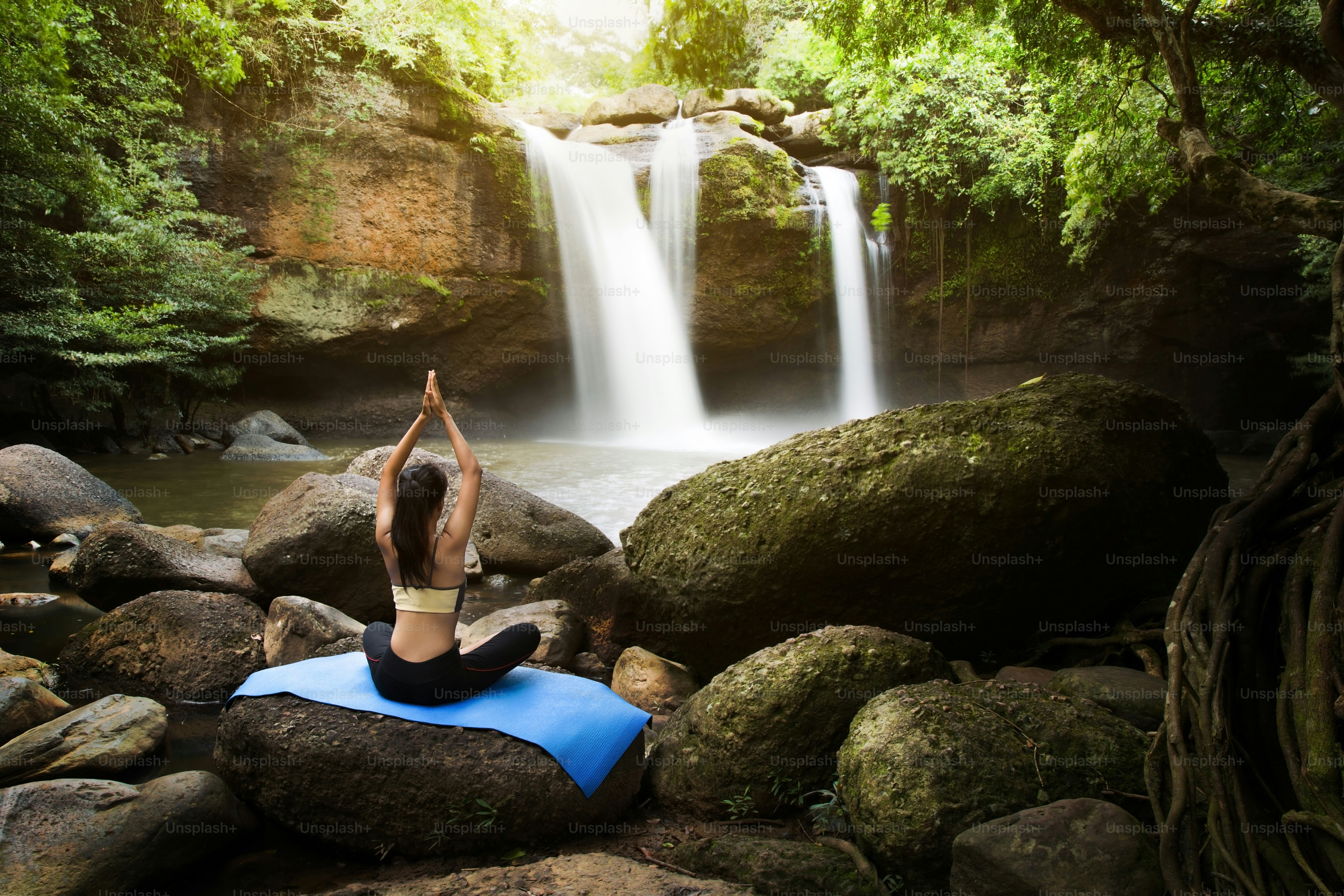 Young woman in a yoga pose at the waterfall, she felt relaxed. The ...