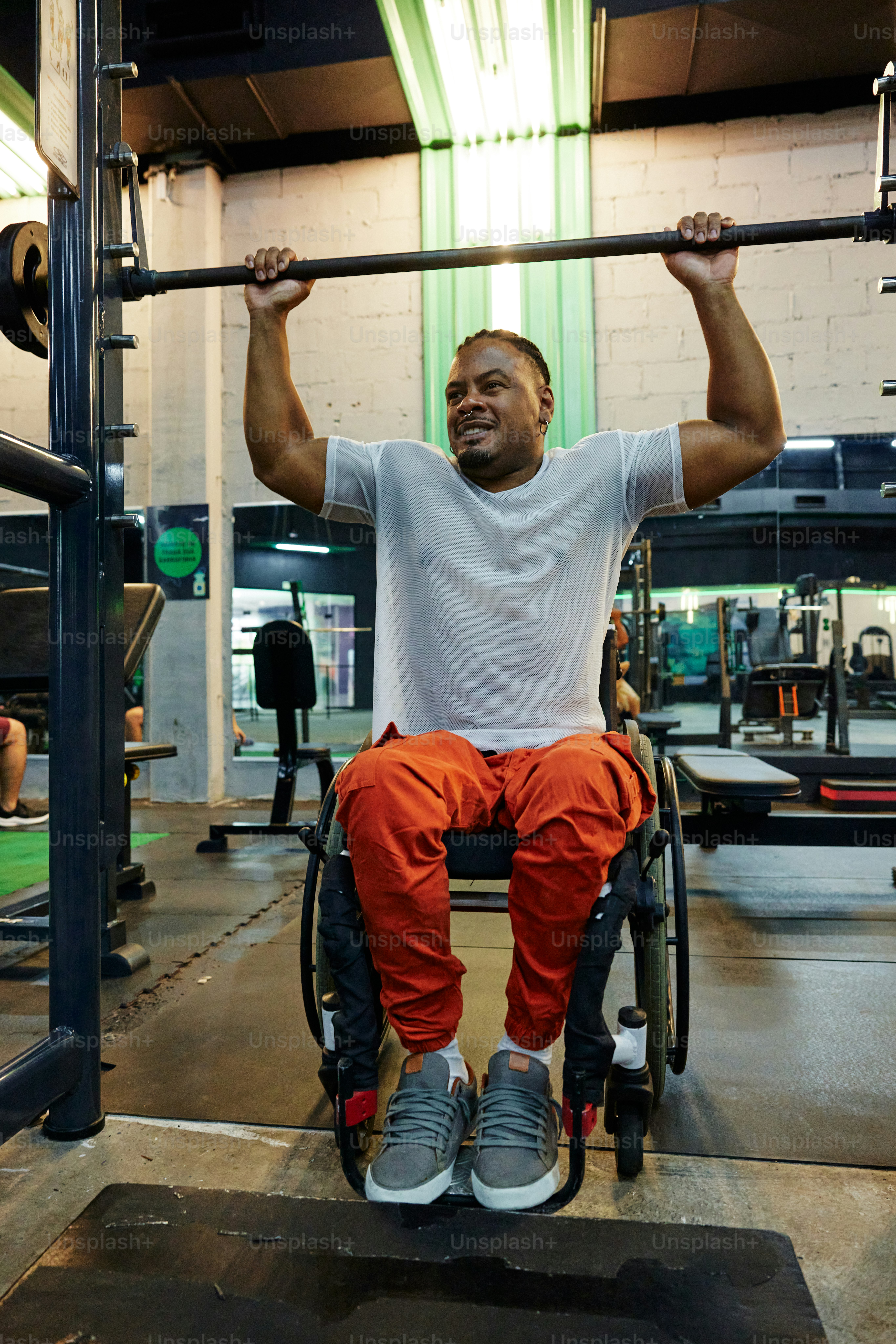 A man in a wheelchair lifts a bar in a gym photo – Working out Image on ...
