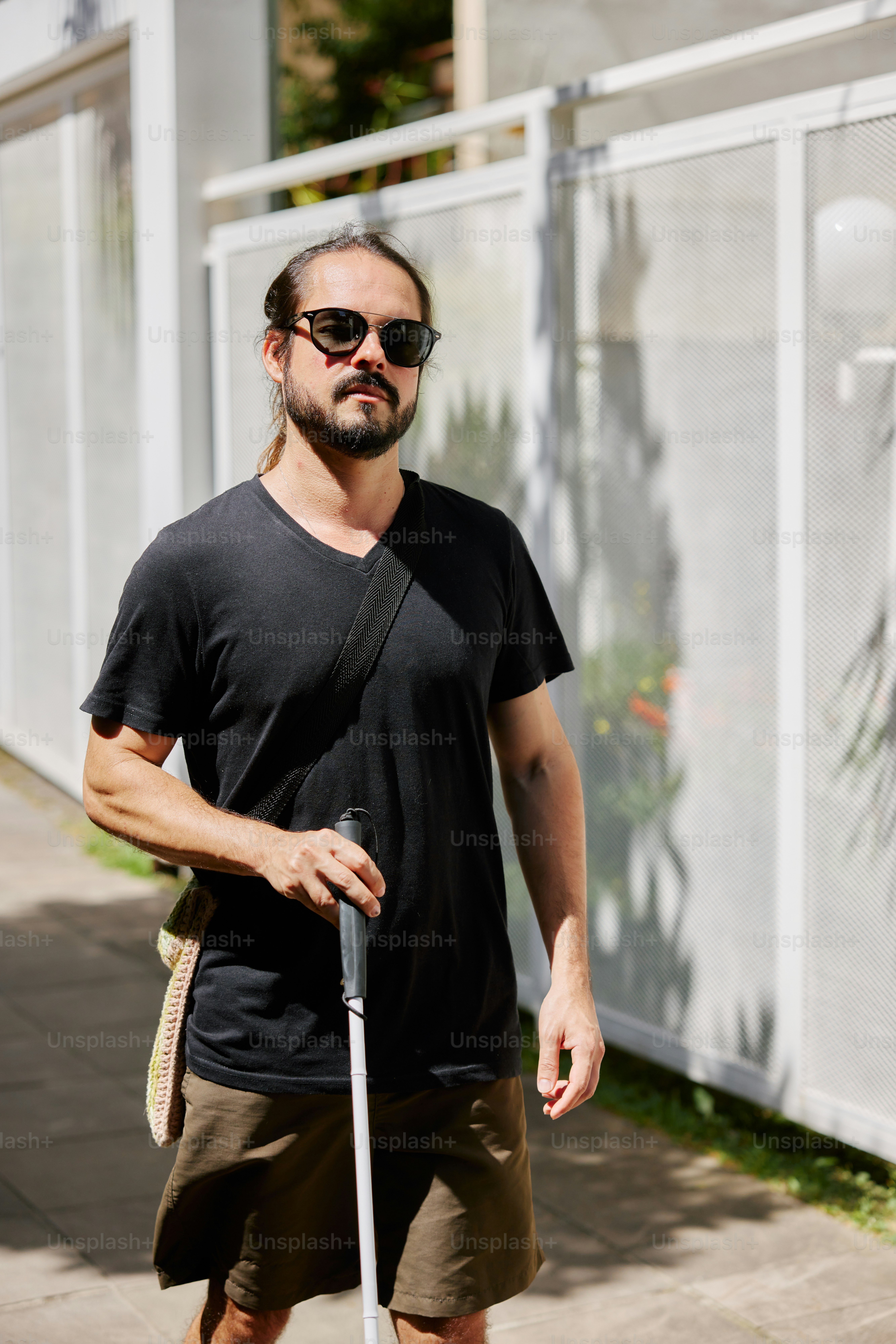 A man with a cane walking down a sidewalk photo – Differently abled ...