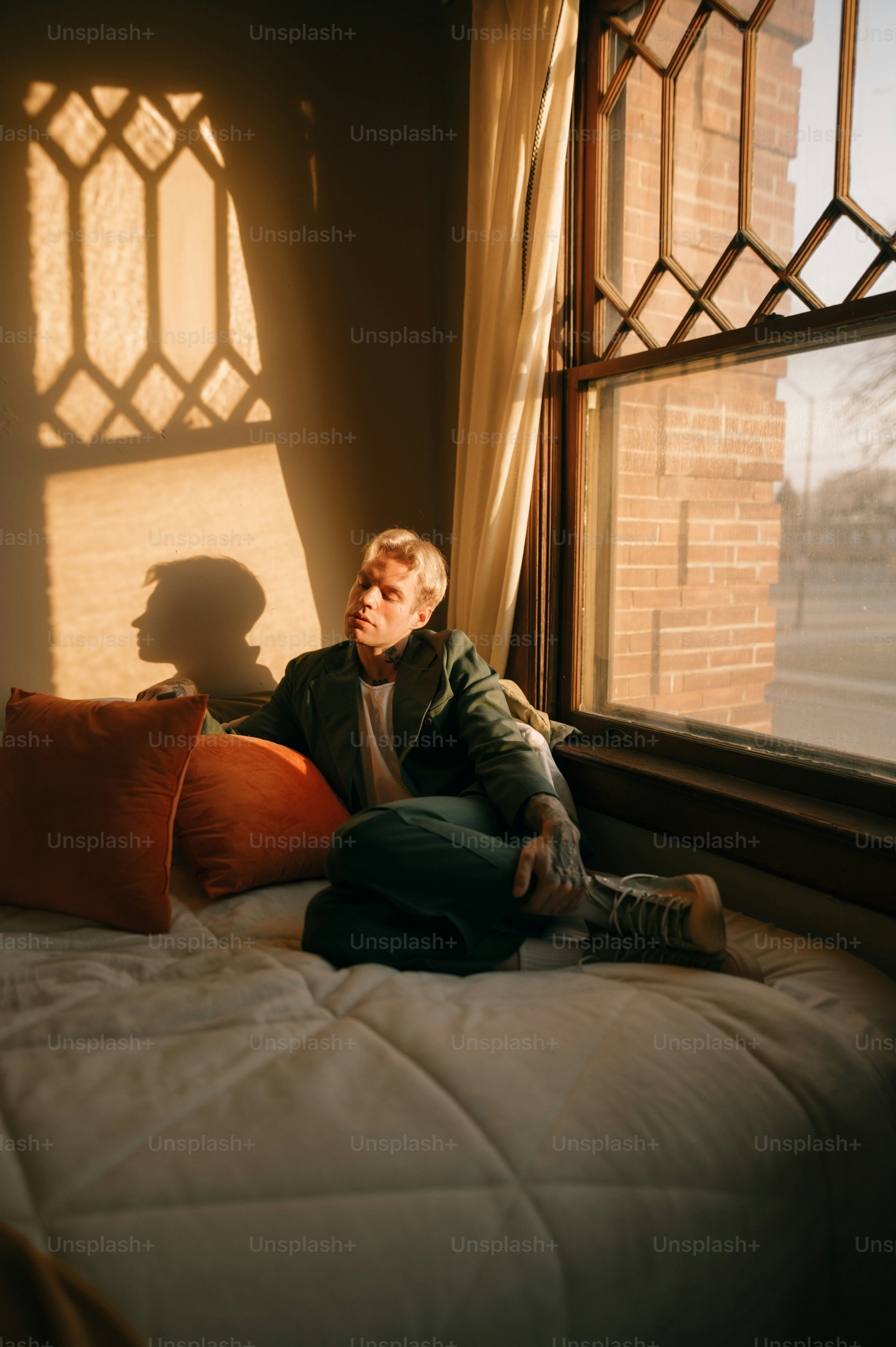 Foto Una persona sentada en una cama – Masculino Imagen en Unsplash