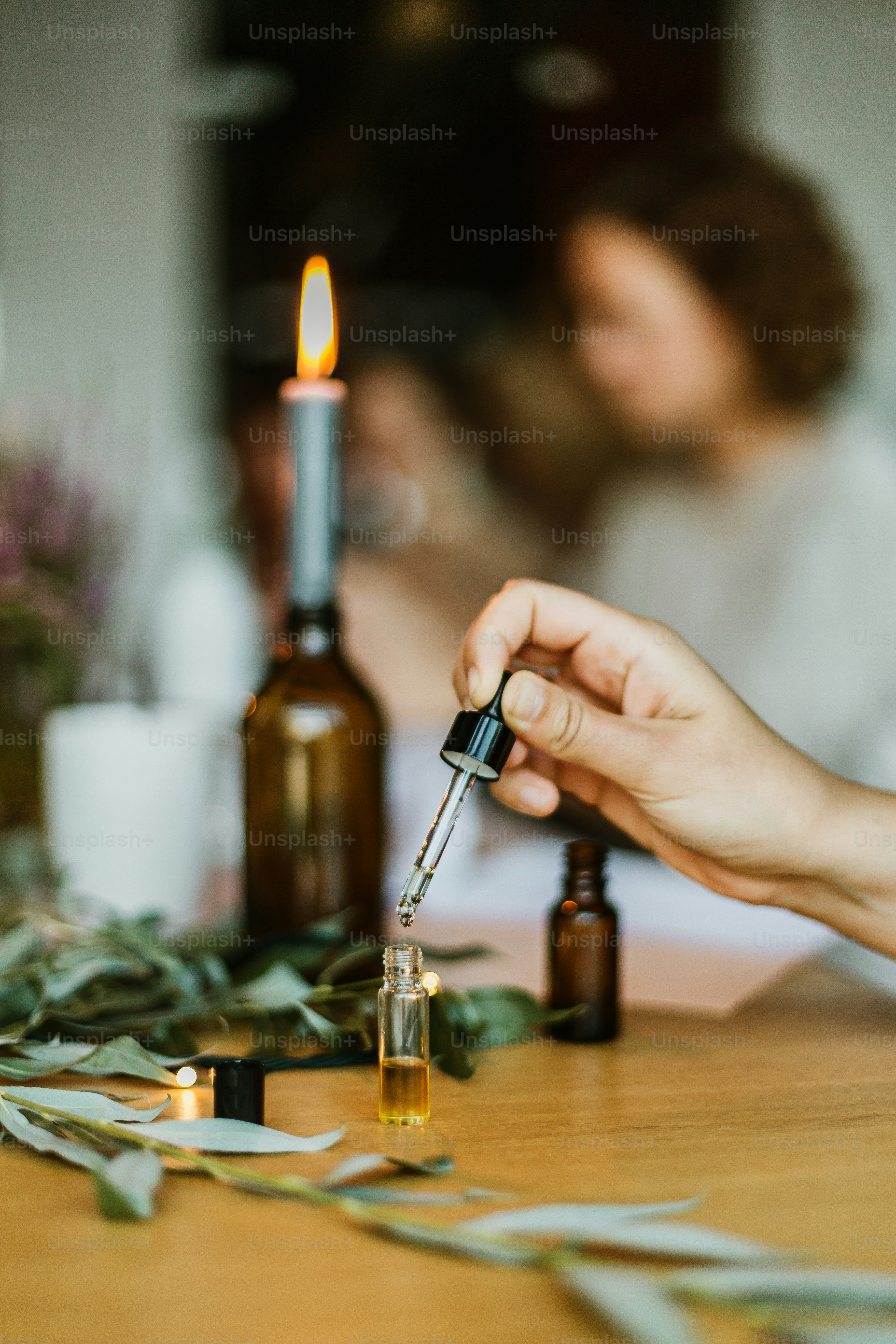 A person lighting a candle on a table photo – Oil bottle Image on Unsplash