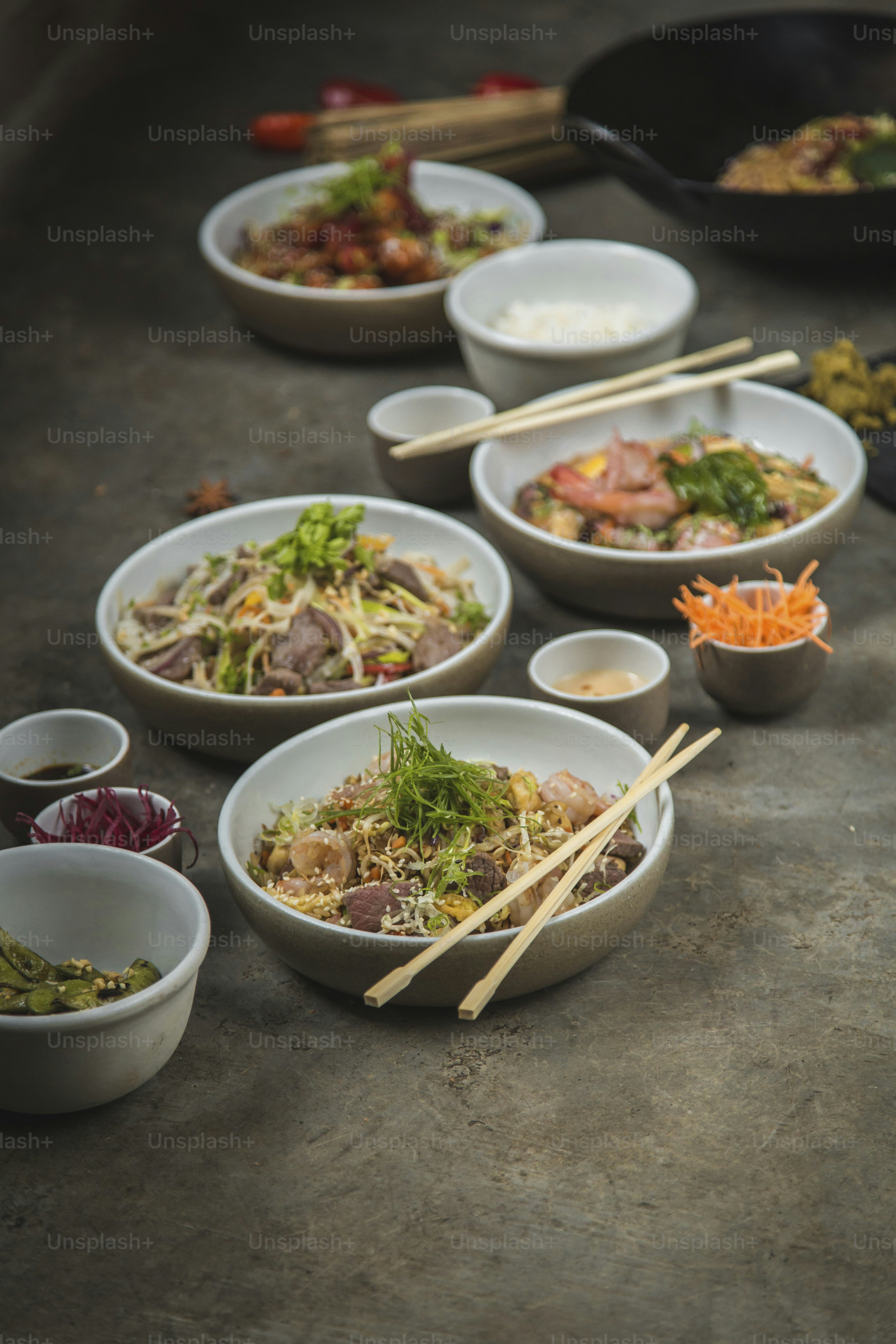 A table topped with bowls of food and chopsticks photo – Chicken salad ...