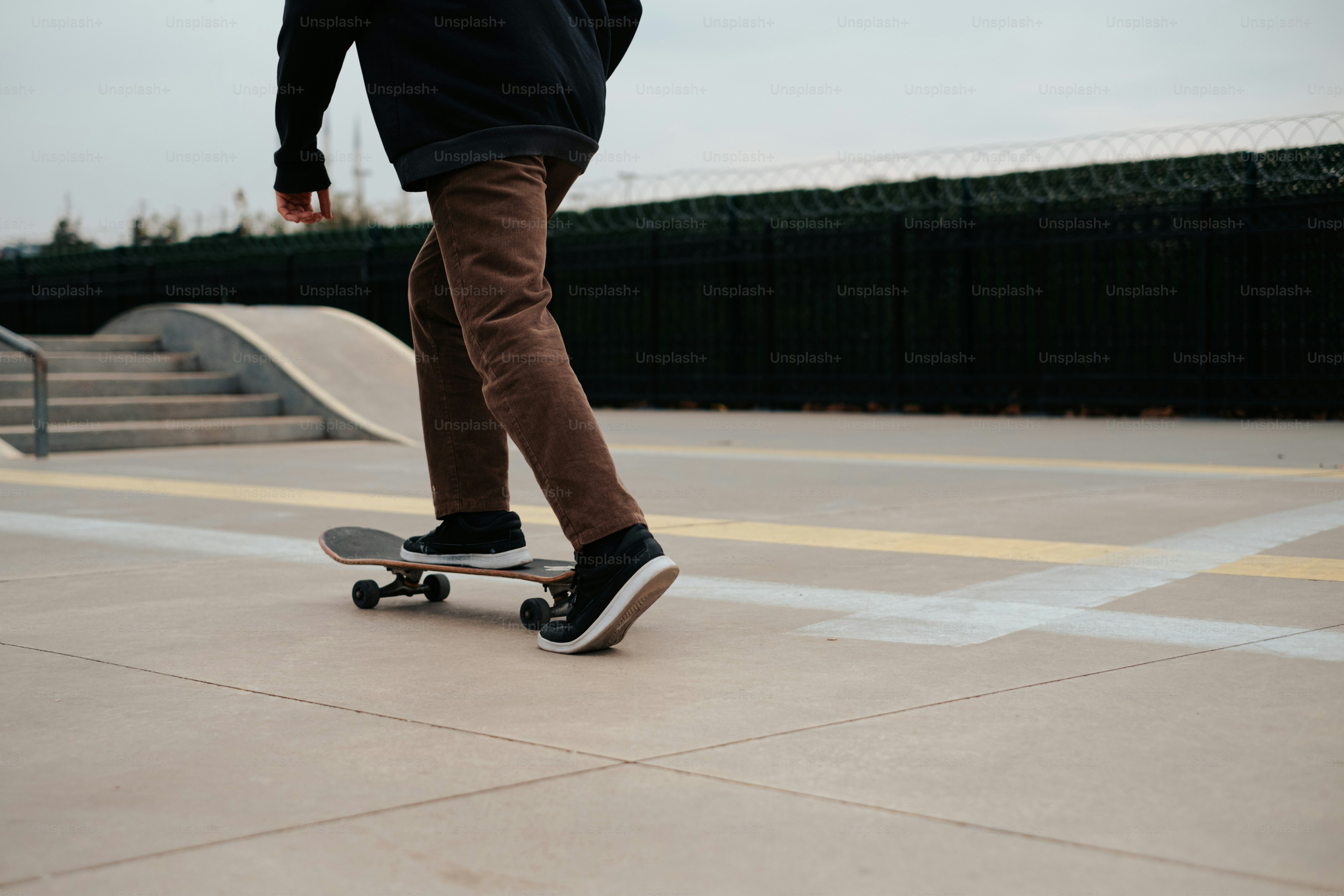 A man riding a skateboard down a sidewalk photo – Skateboarder Image on ...