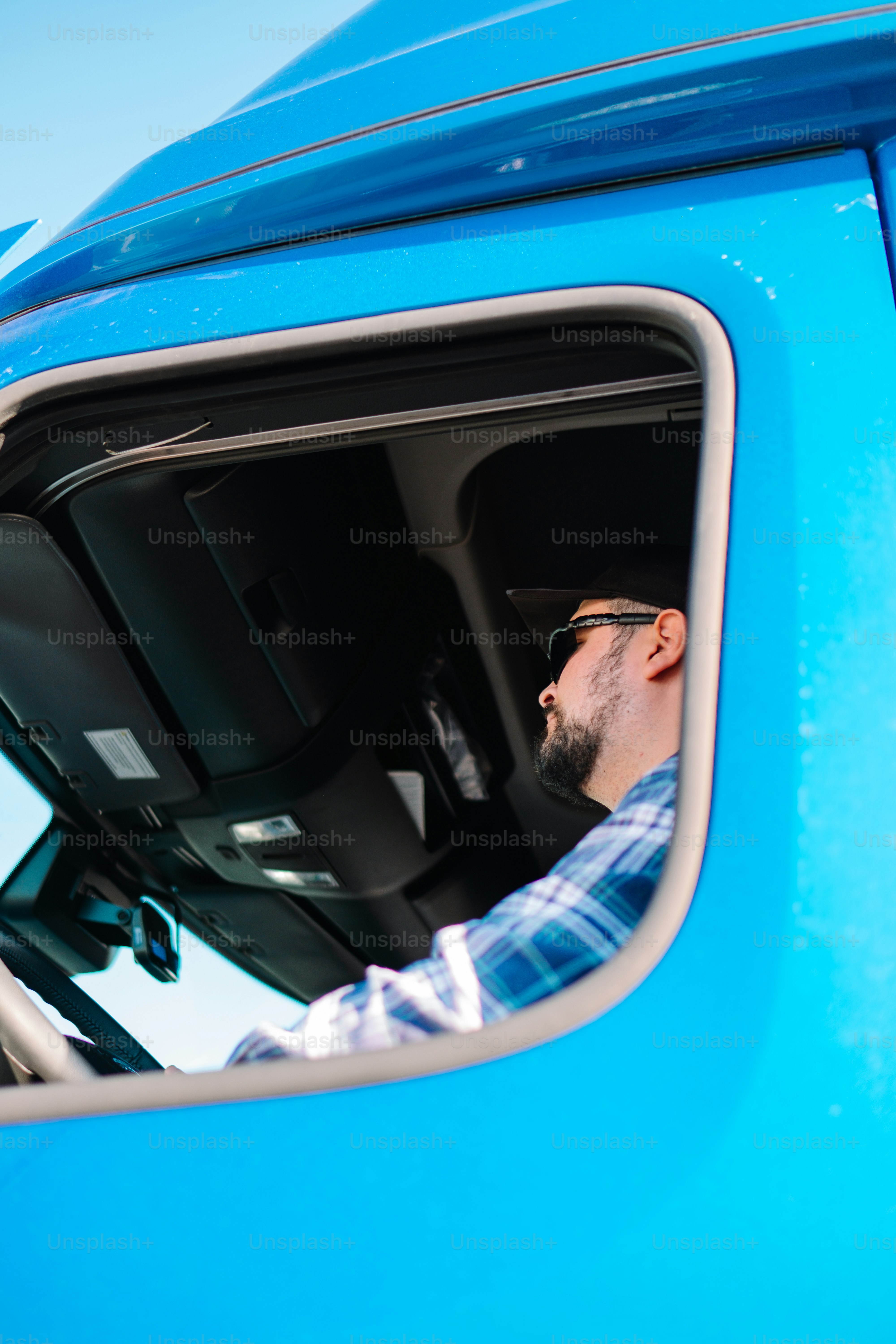 A man sitting in the drivers seat of a blue truck photo – Truck driver ...
