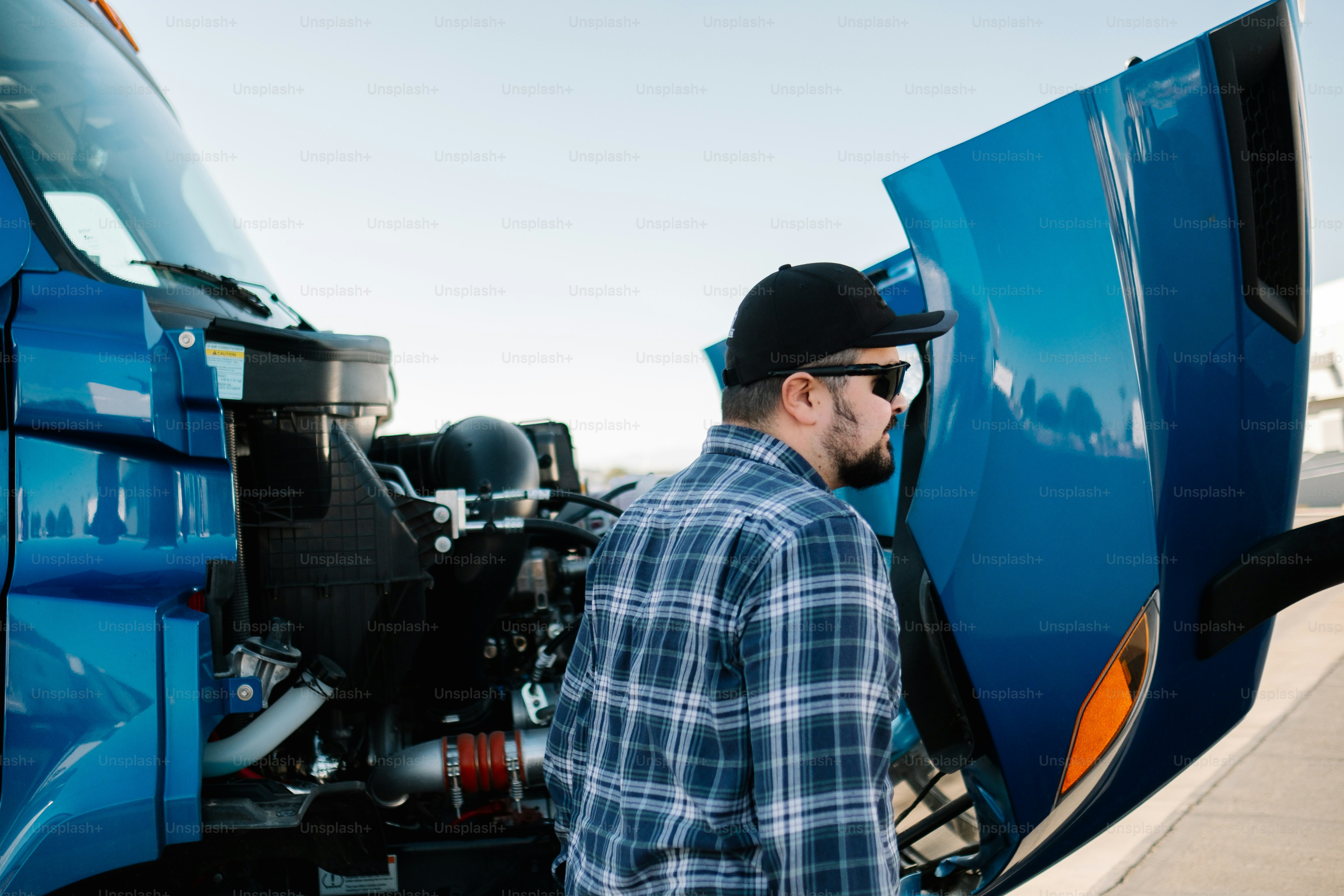 A man standing next to a blue semi truck photo – Truck driver Image on ...