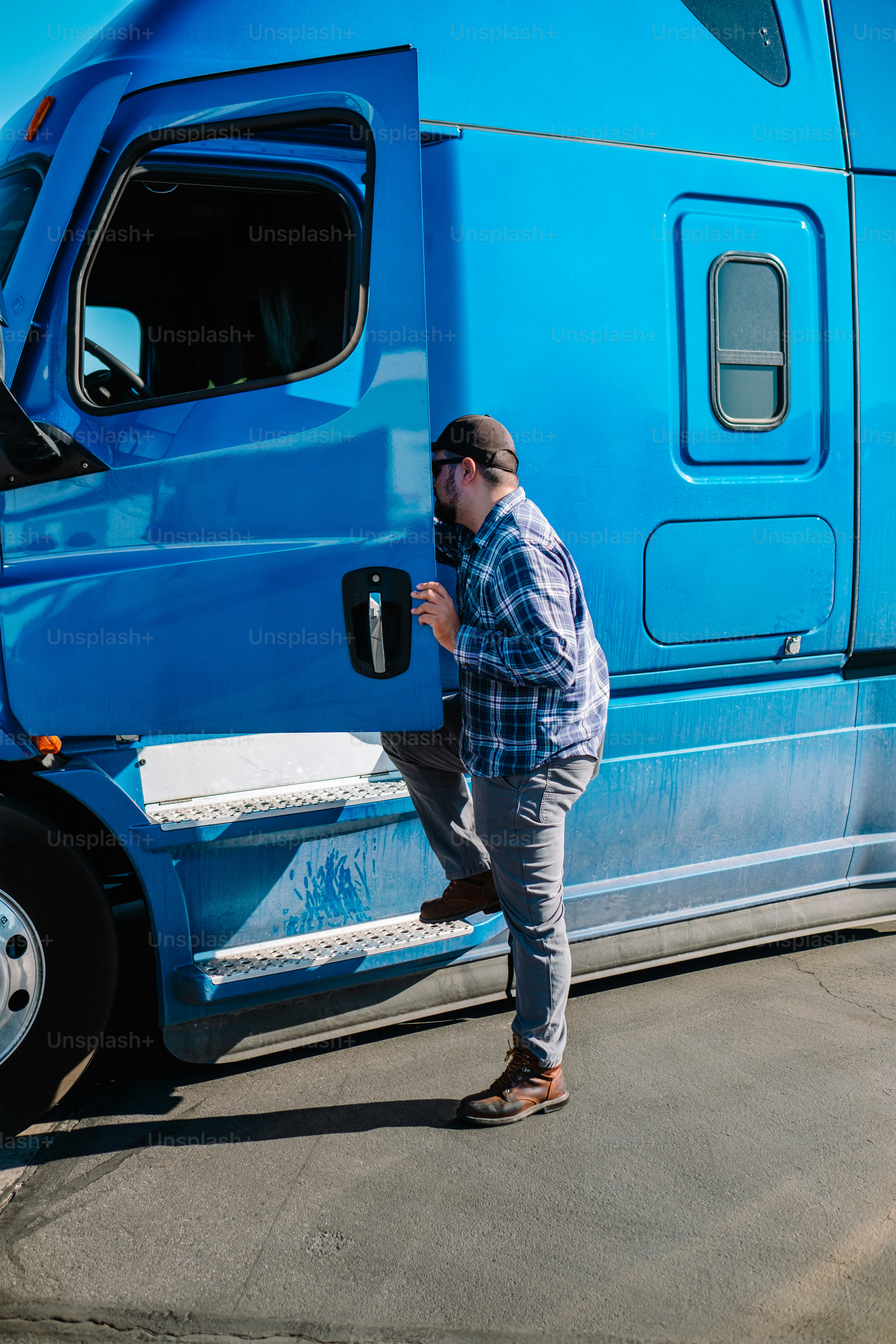 A man standing next to a blue semi truck photo – Driver Image on Unsplash