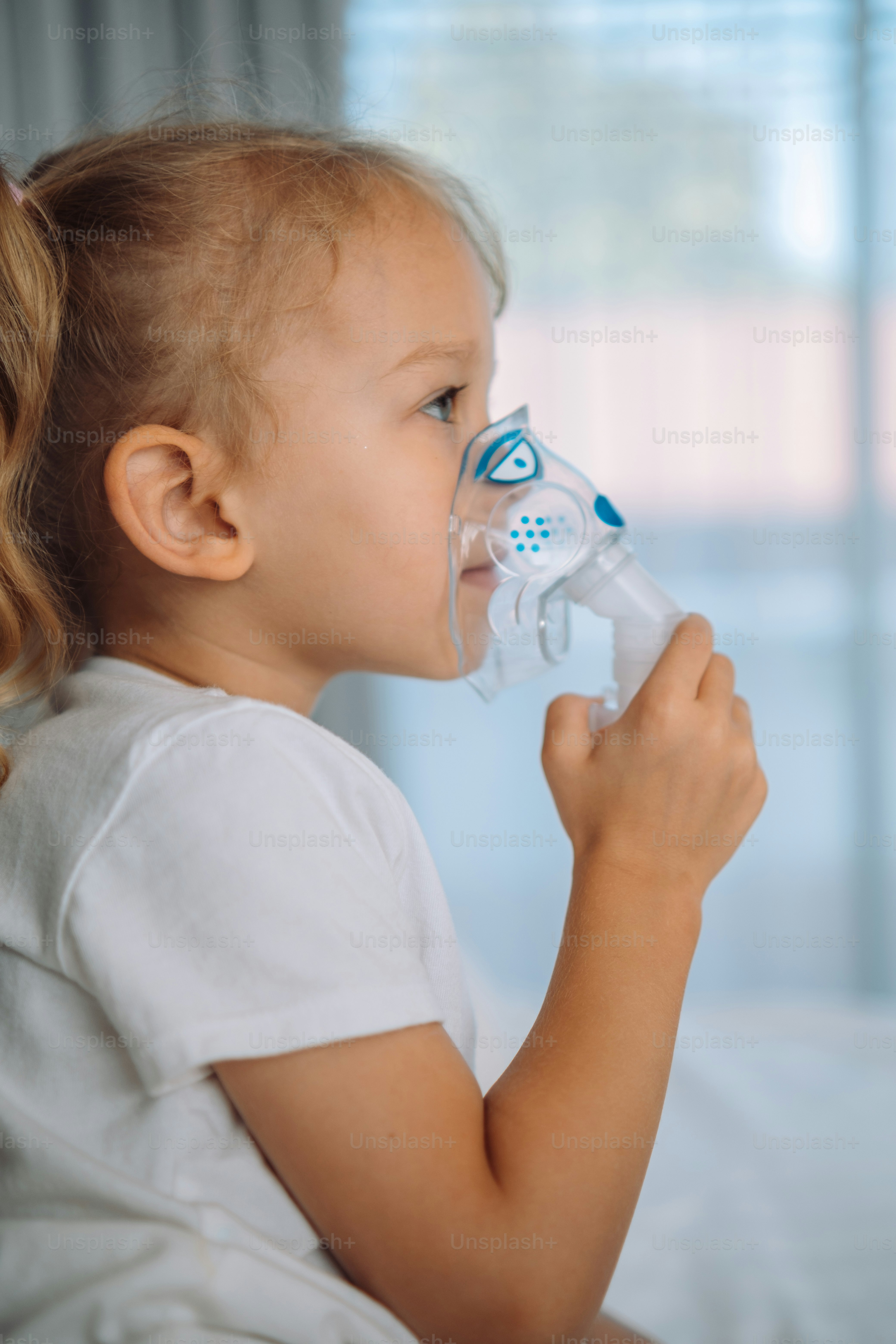 A little girl sitting on a bed with a pacifier in her mouth photo ...