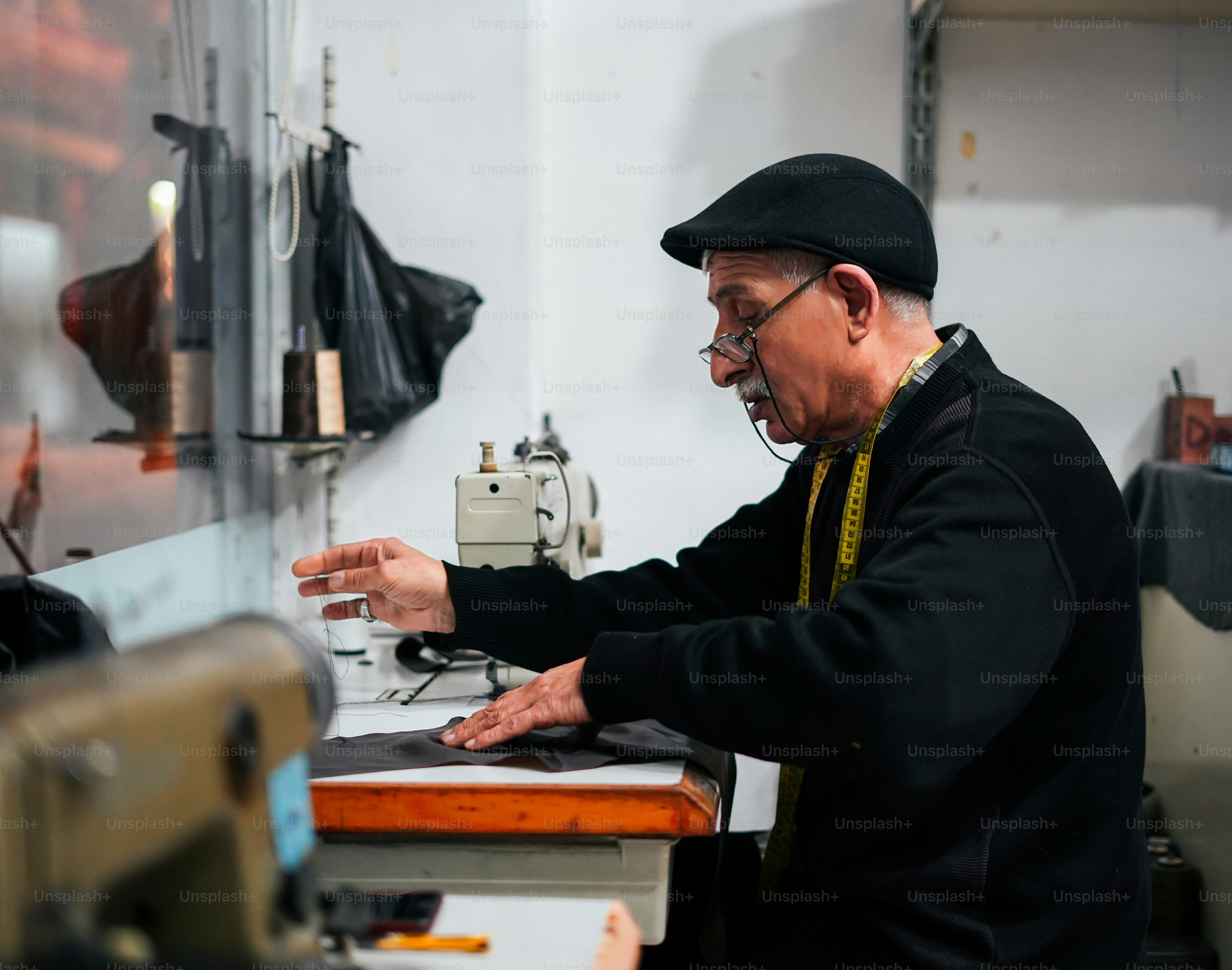 An older man working on a sewing machine photo – Master tailor Image on ...