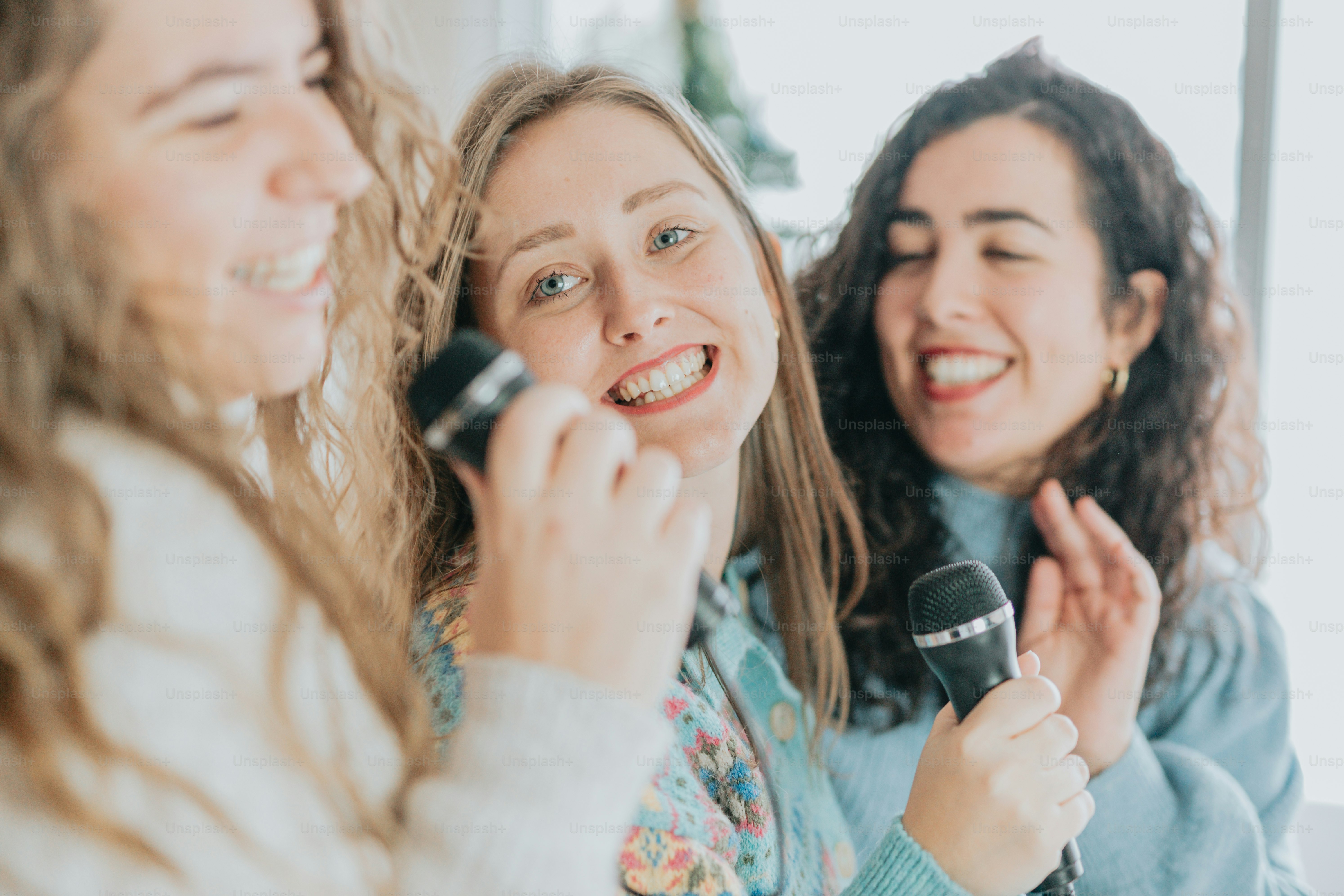 Three girls are laughing while one of them is holding a microphone ...