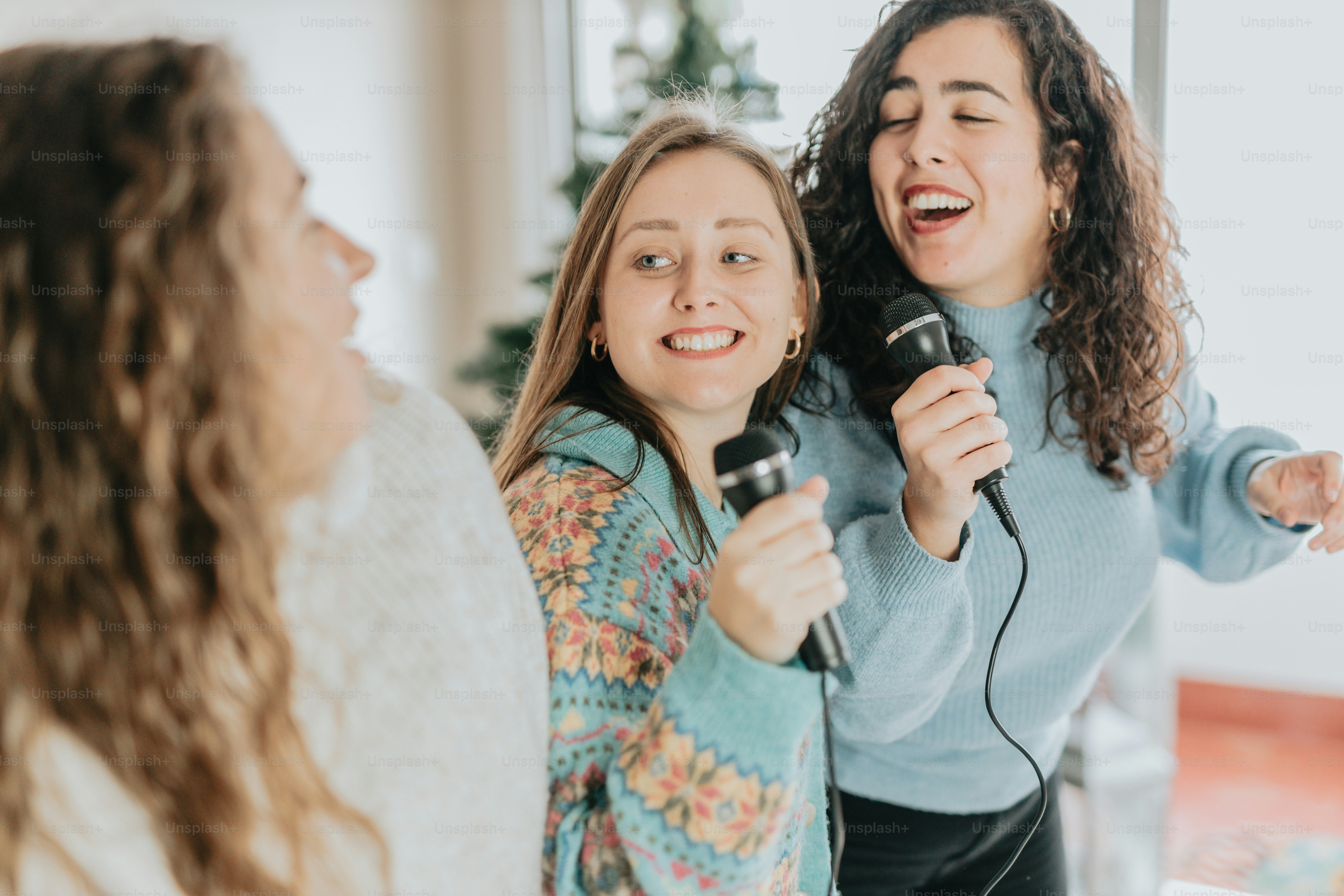 A group of women singing into microphones while sitting on a couch ...