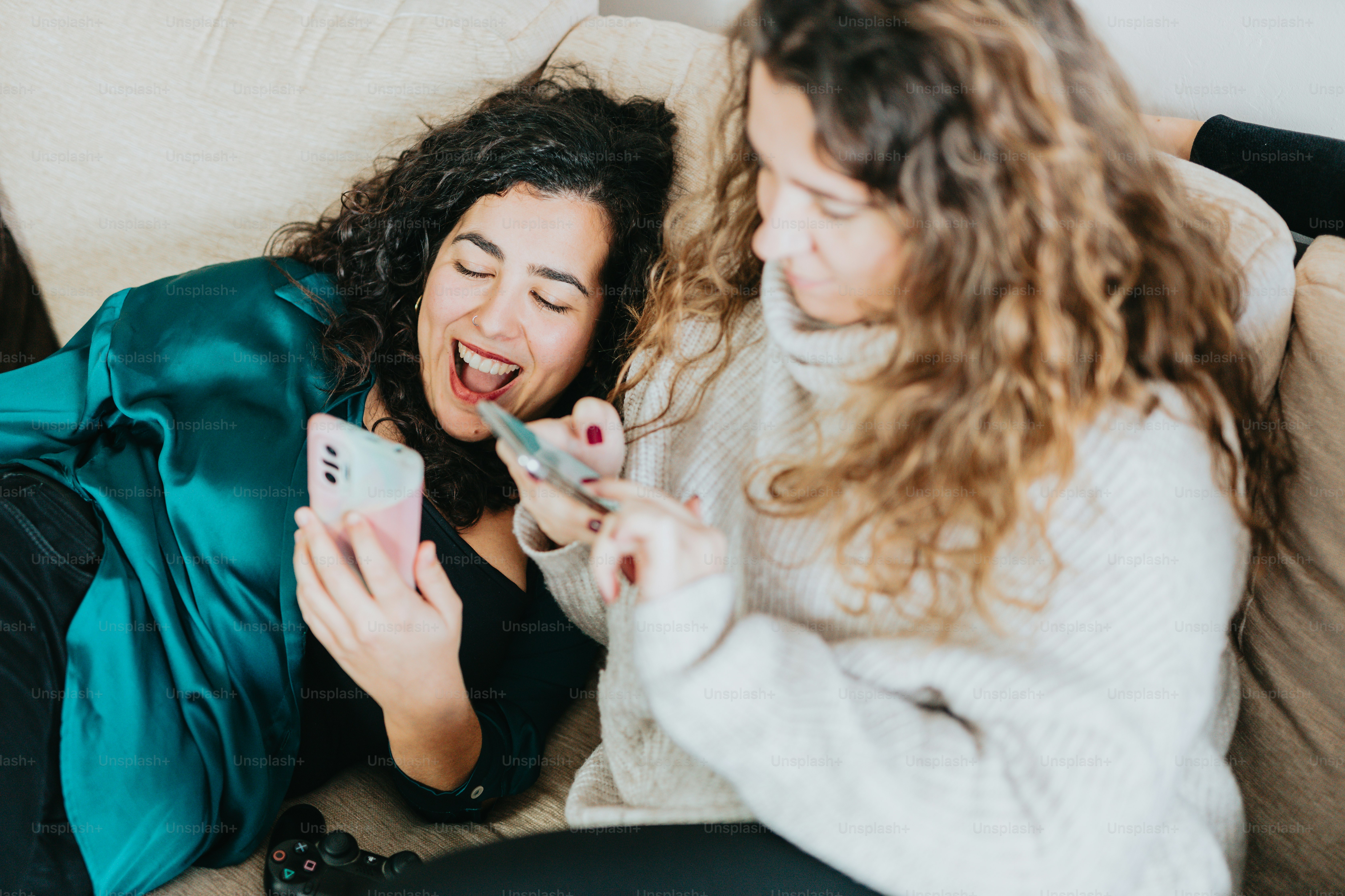 Two women laughing while looking at their cell phones photo – Social ...
