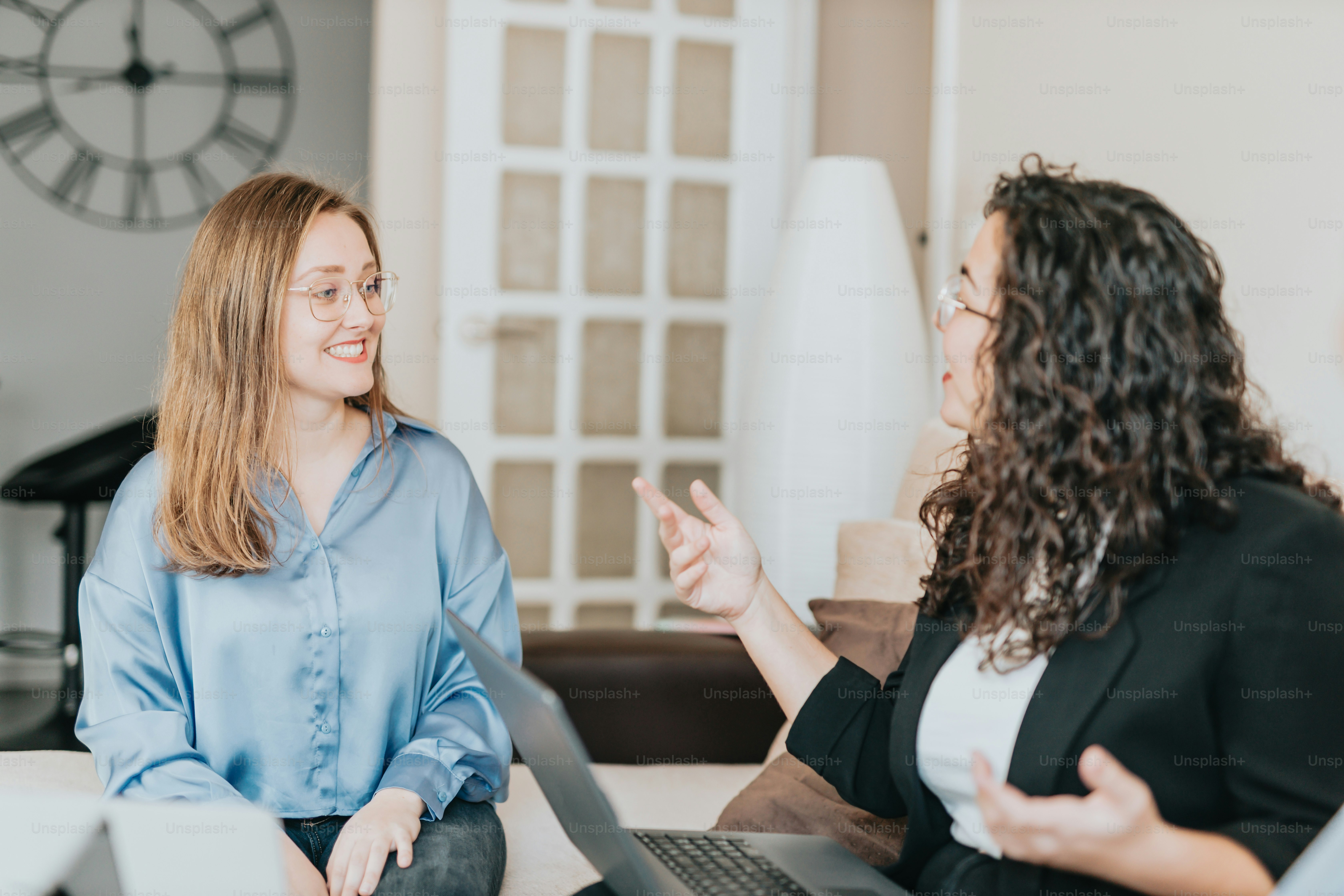 Two women sitting on a couch talking to each other photo – Conversation ...