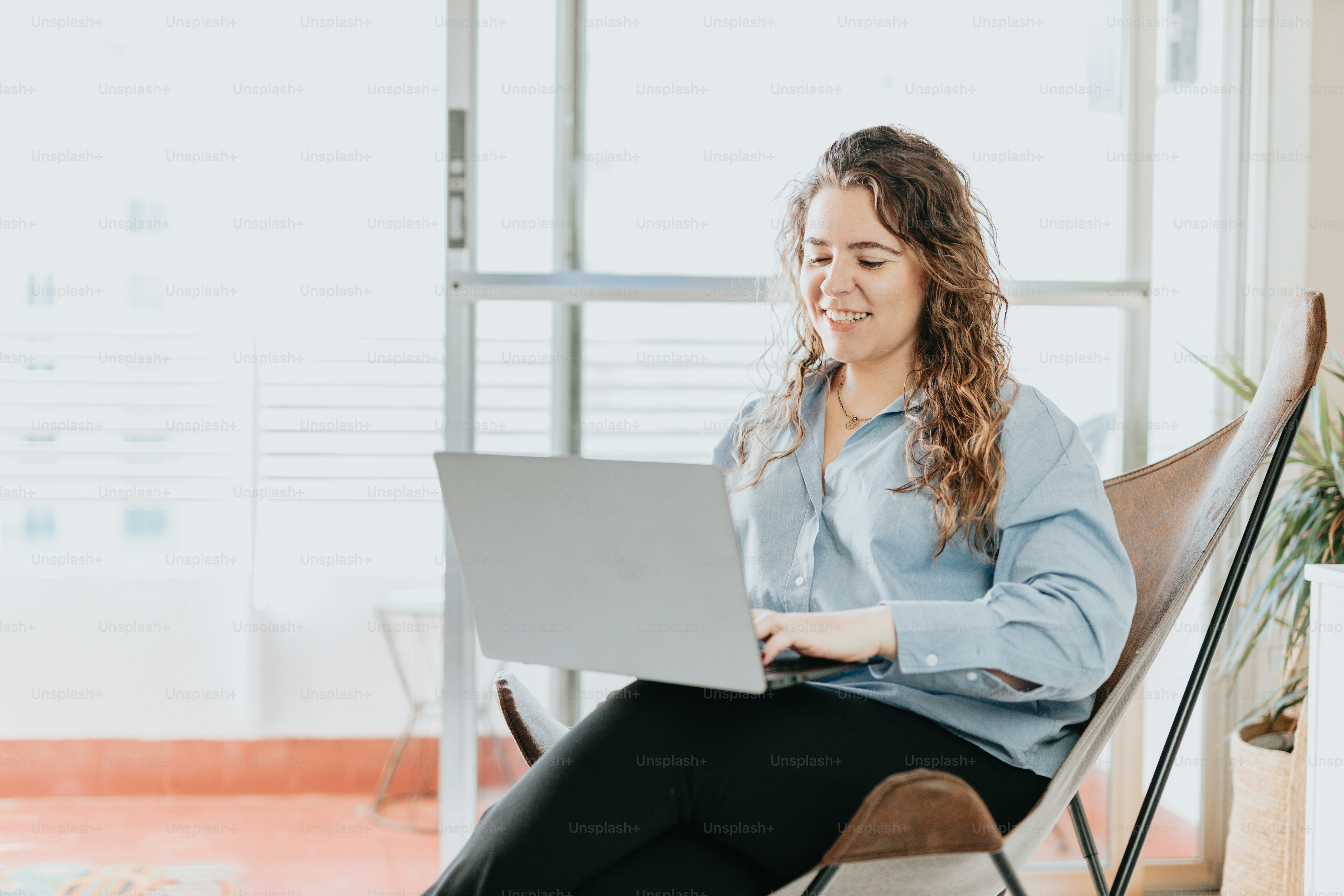 A woman sitting in a chair using a laptop computer photo – Female Image ...