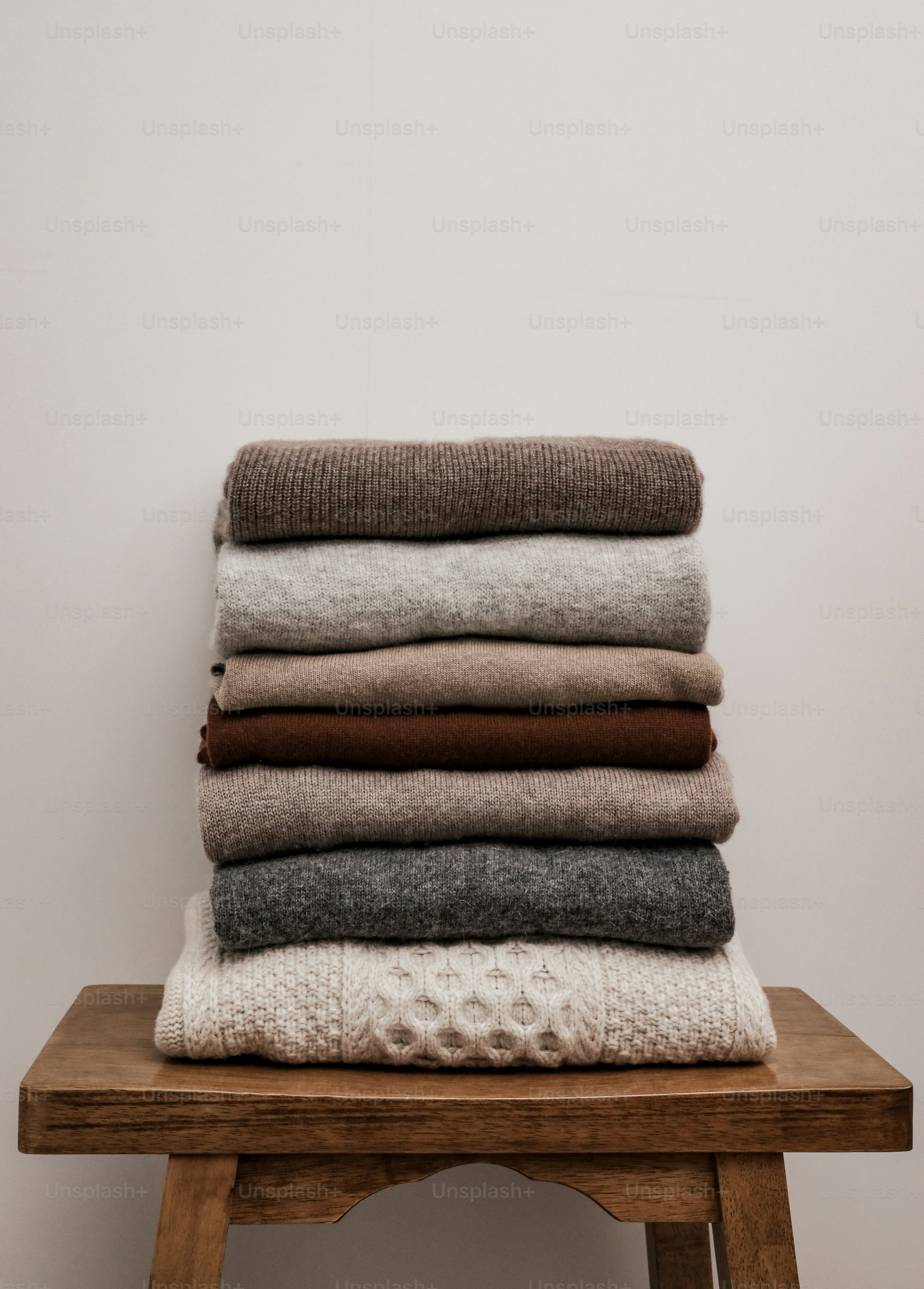 A stack of folded blankets sitting on top of a wooden table photo ...