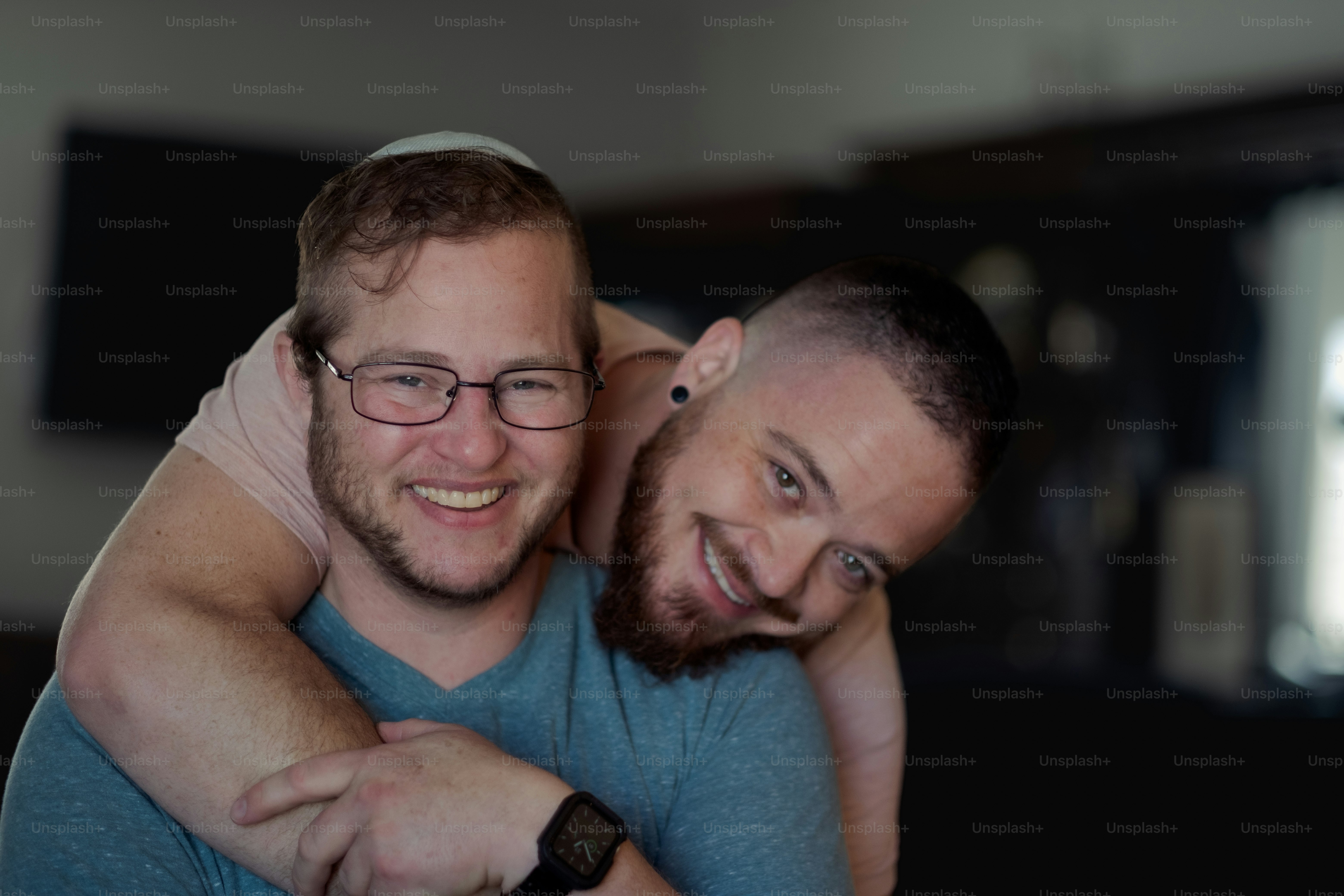 Two men hugging each other in a living room photo – Transman Image on ...