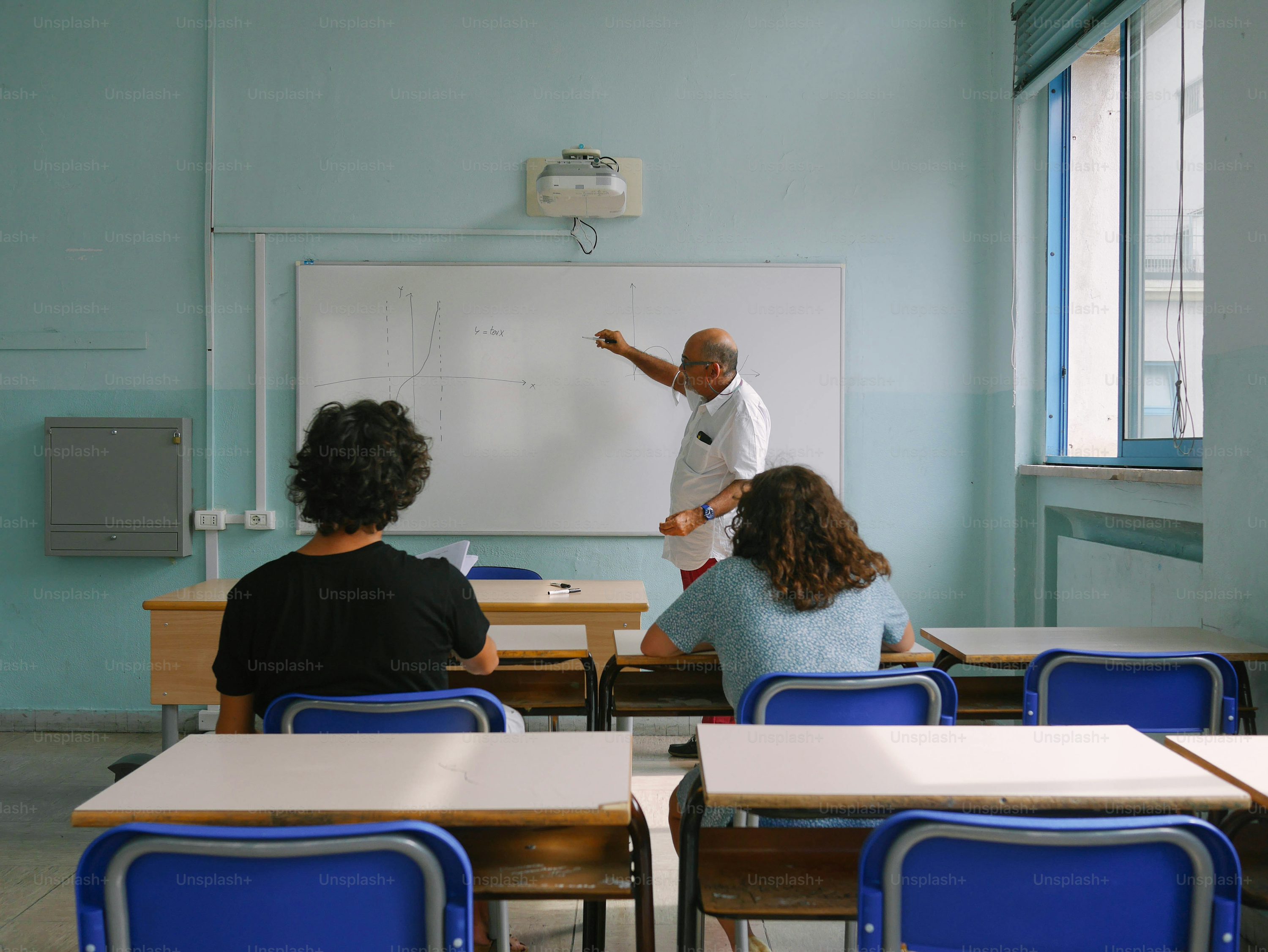 Um grupo de pessoas sentadas em carteiras em uma sala de aula foto ... Um grupo de pessoas sentadas em carteiras em uma sala de aula foto ...