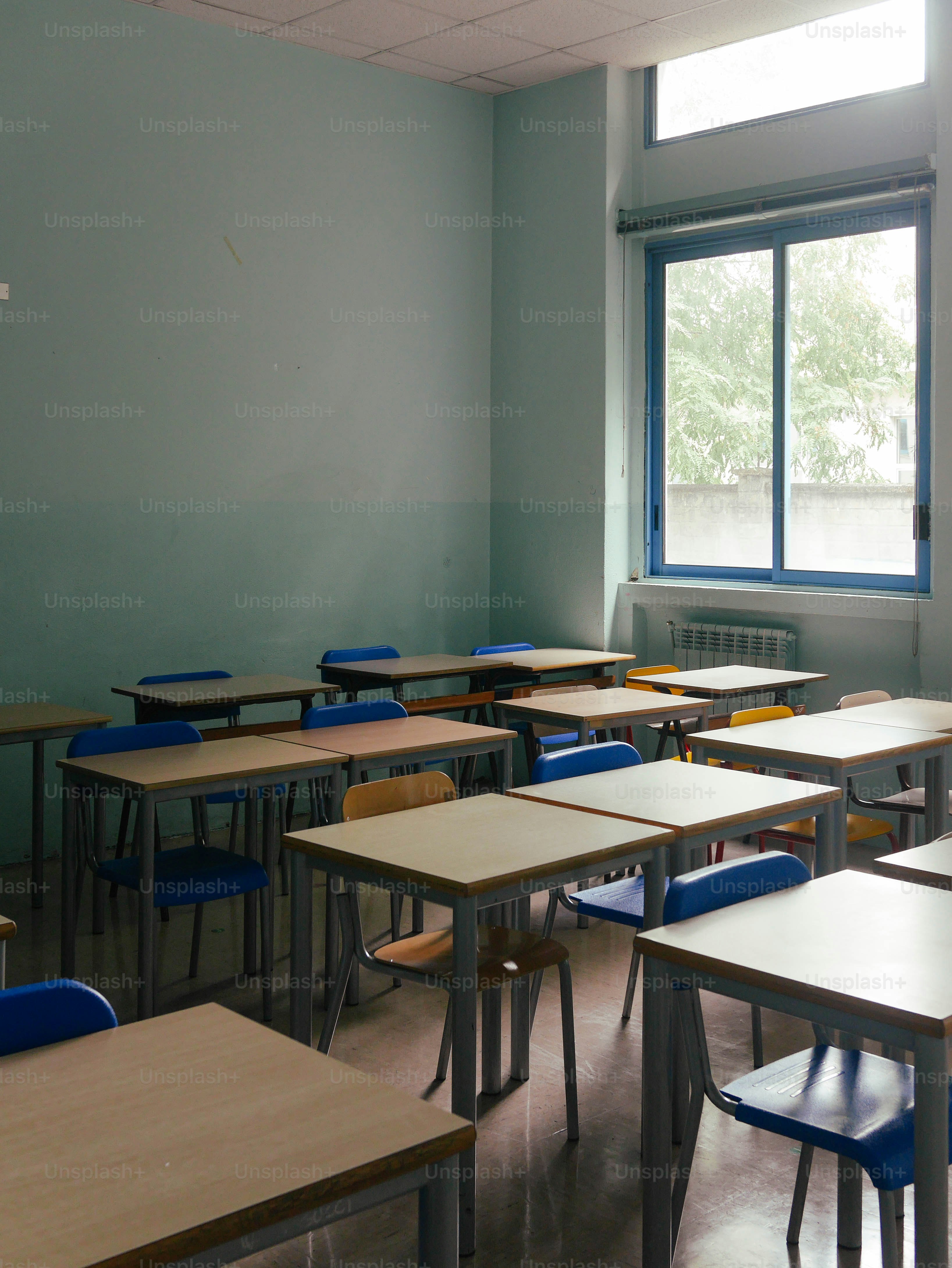 A classroom with desks and chairs and a window photo – Chairs Image on ...