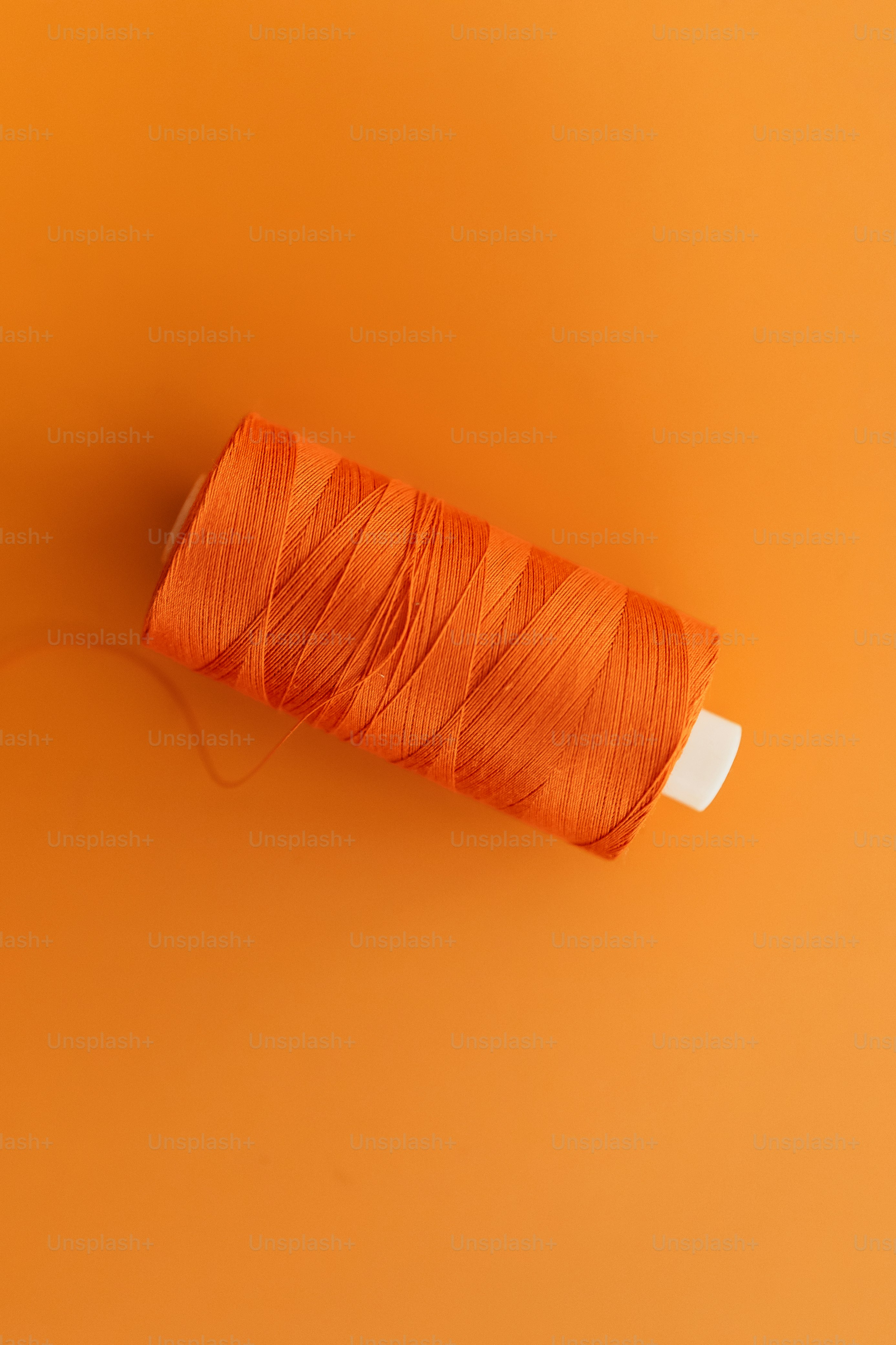 A spool of thread on an orange background photo – Linen yarn Image on ...