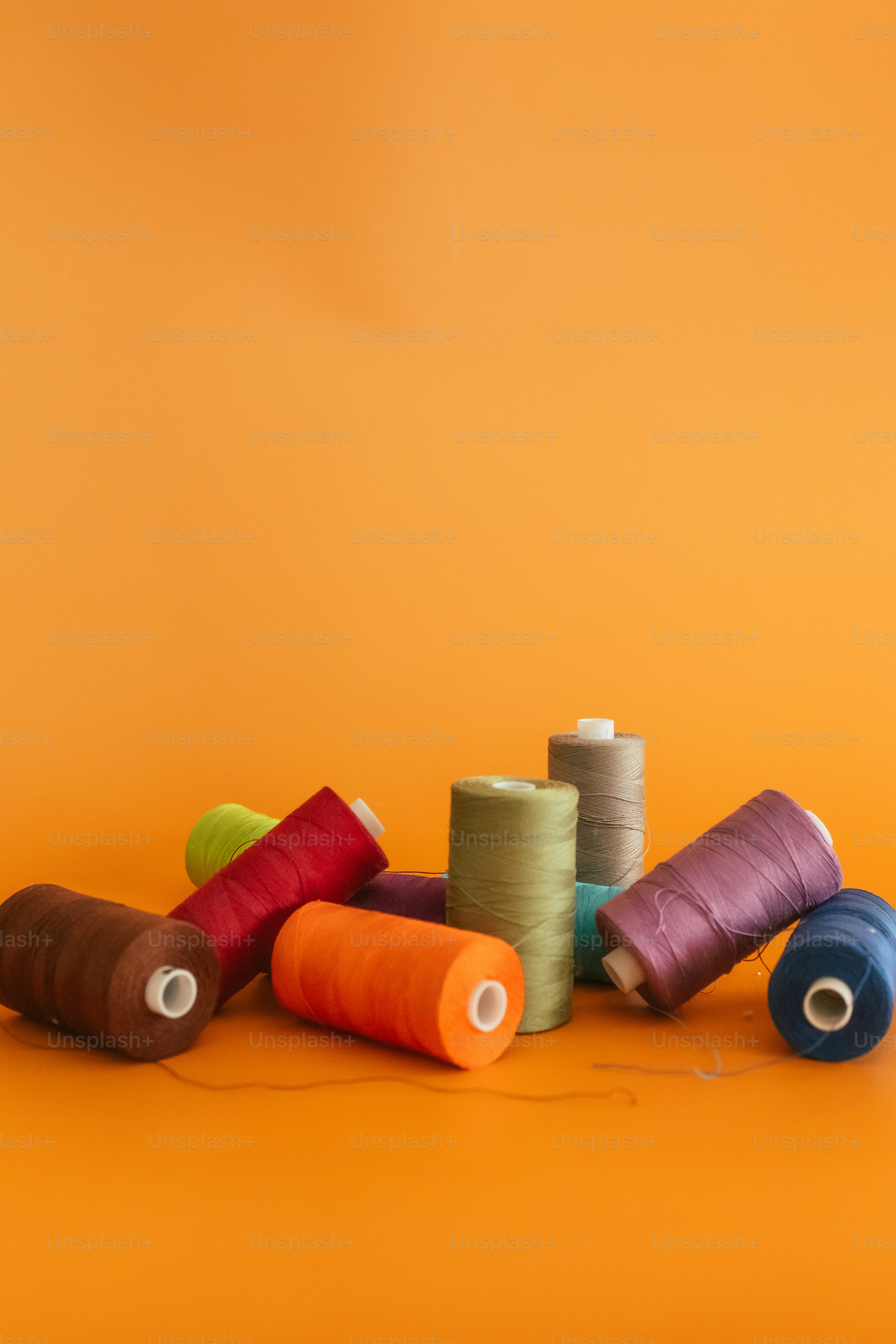 A group of spools of thread sitting on top of a table photo – Orange ...