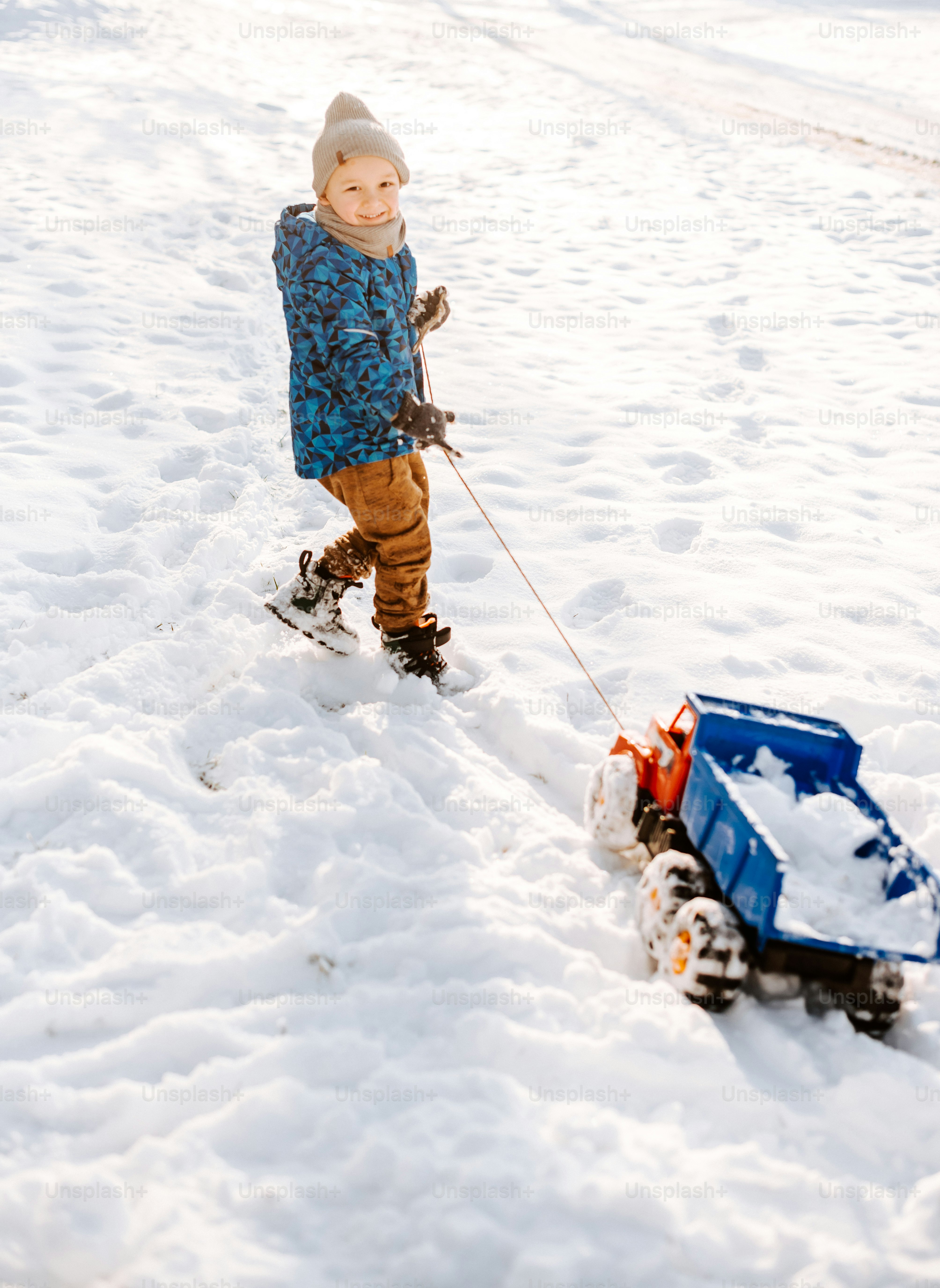 A young boy pulling a toy car in the snow photo – Kids snow Image on ...