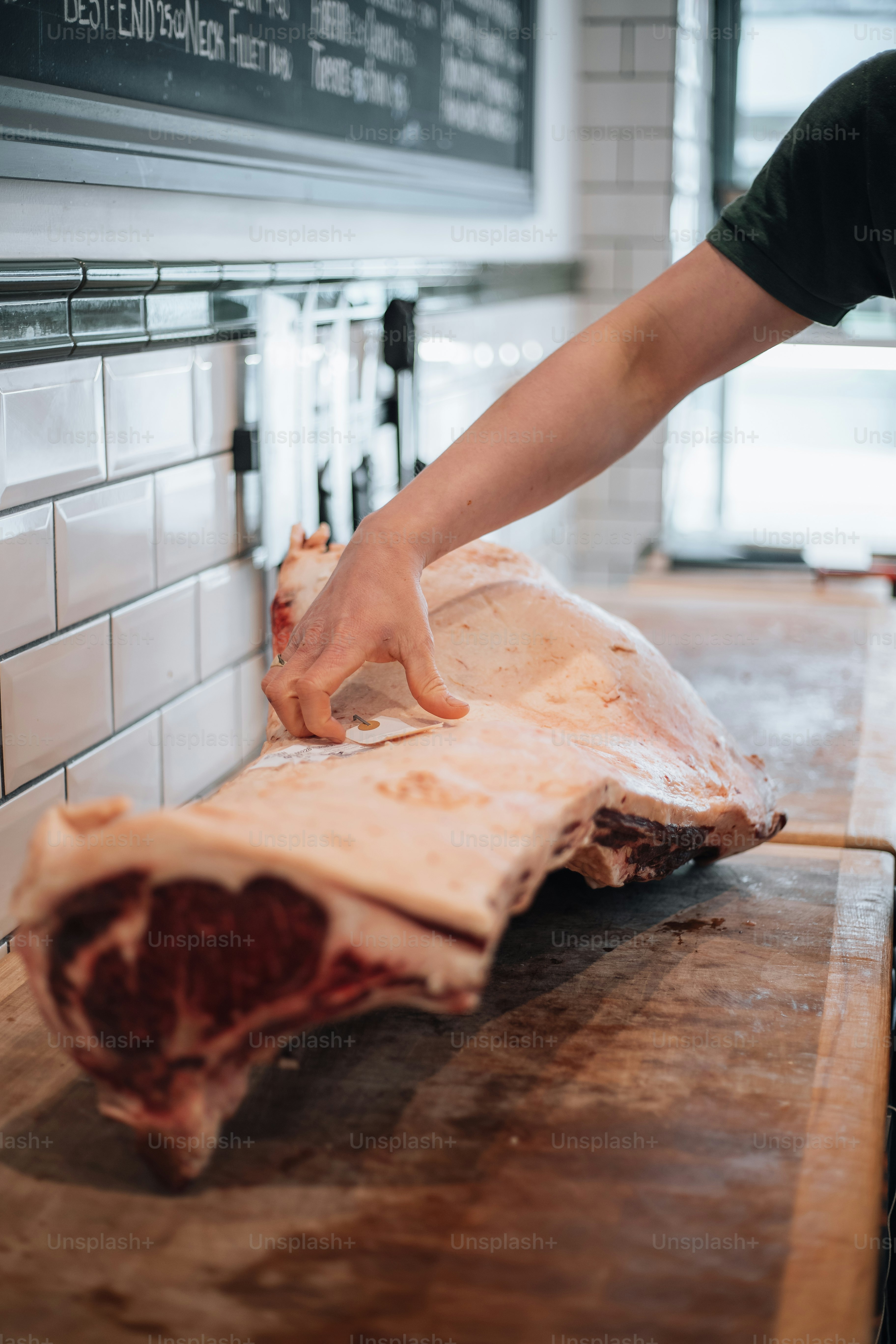 A person cutting up a piece of meat on a cutting board photo – Butcher ...