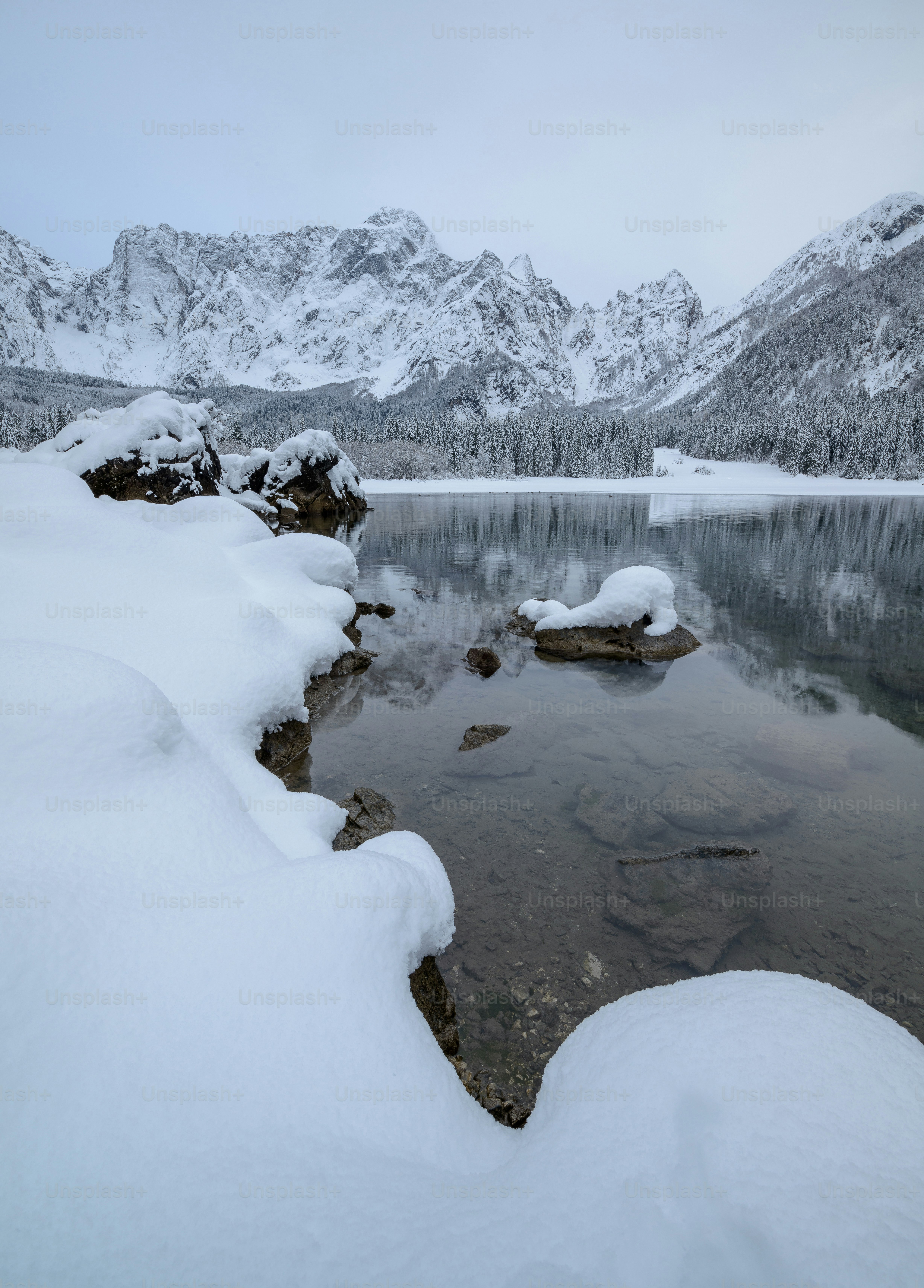 Un lago rodeado de montañas cubiertas de nieve foto – Imagen de ...
