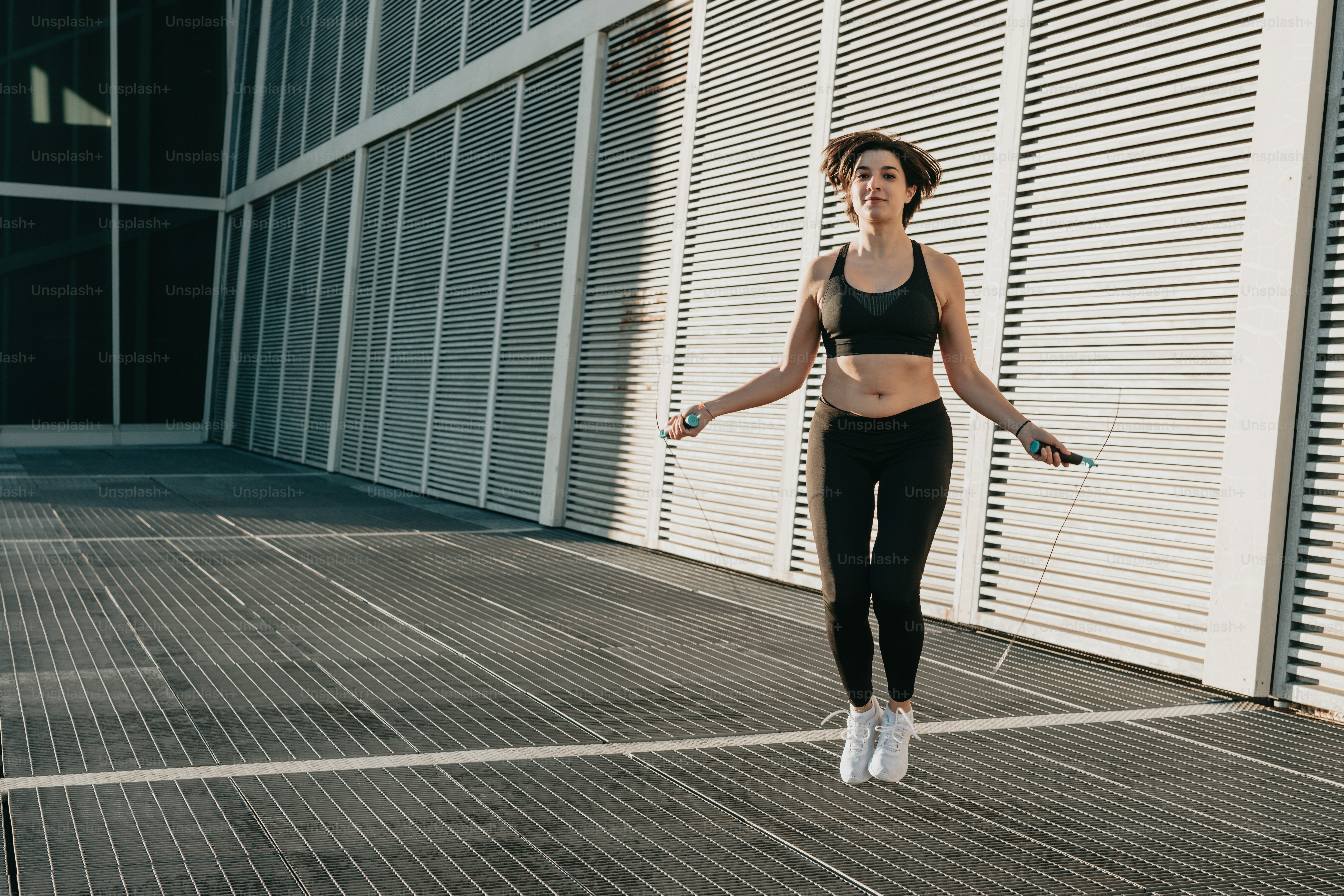A woman in a sports bra top and leggings is jumping in the air photo ...