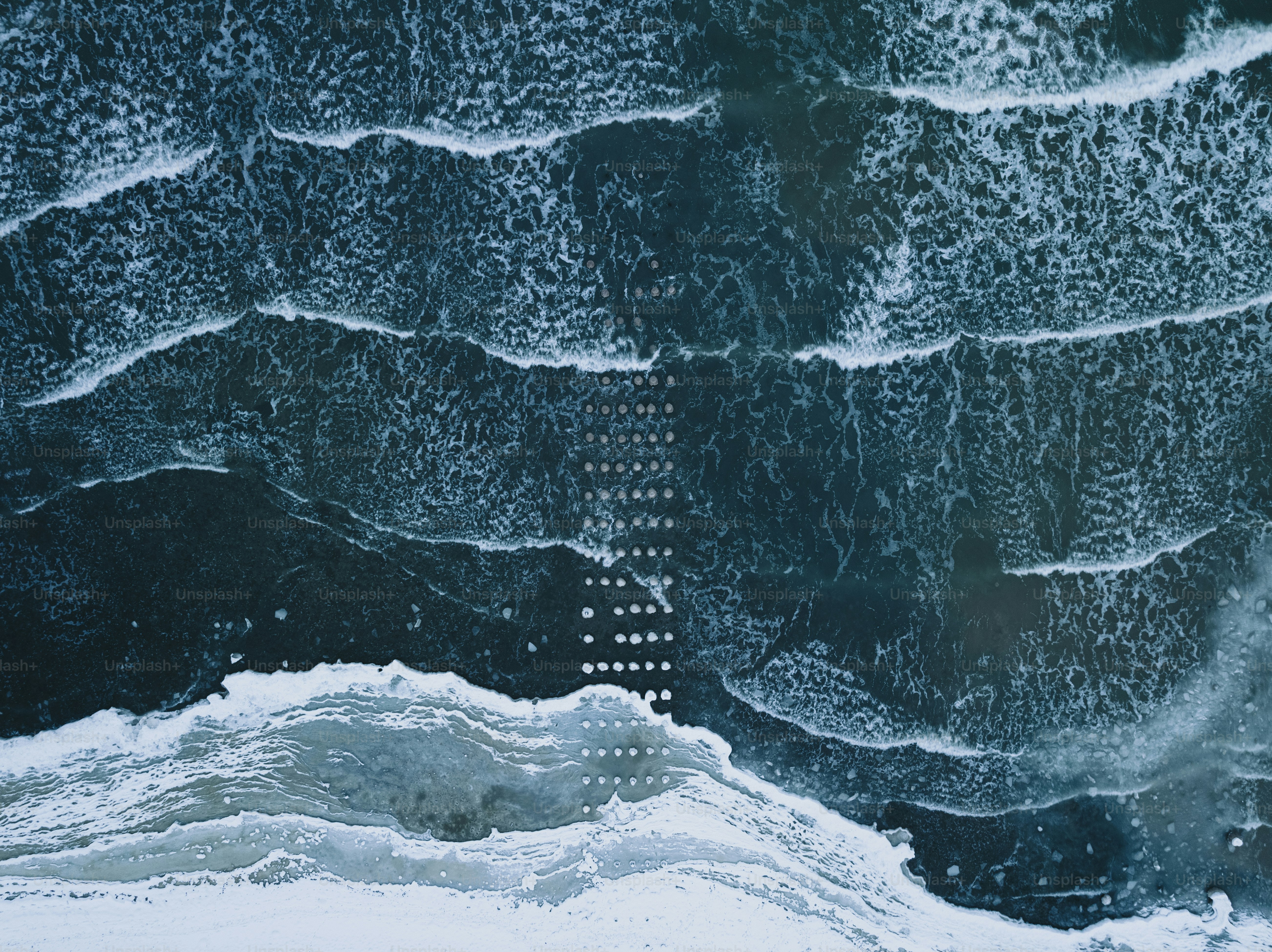 A man riding a snowboard on top of a wave covered ocean photo – Sea ...