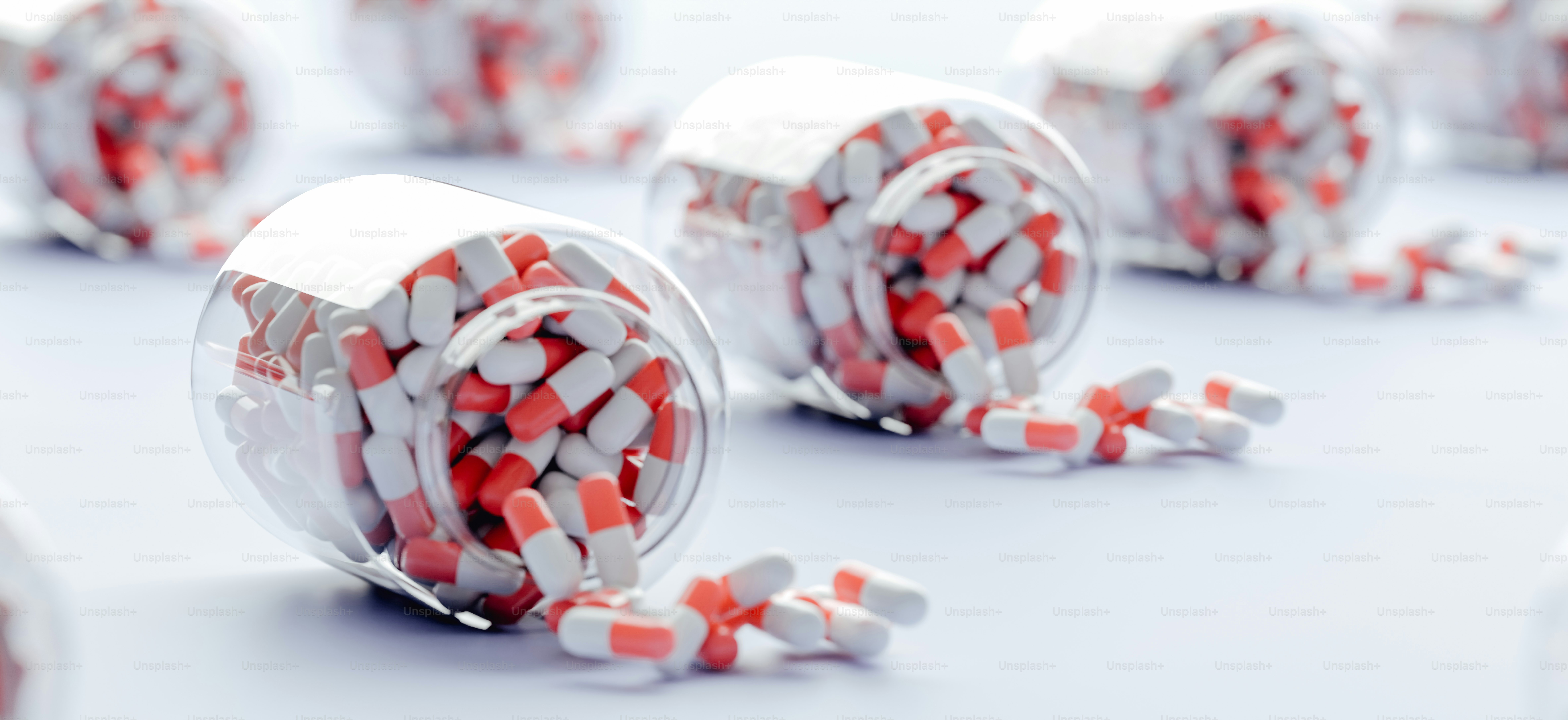 A bunch of red and white pills spilling out of a container photo ...