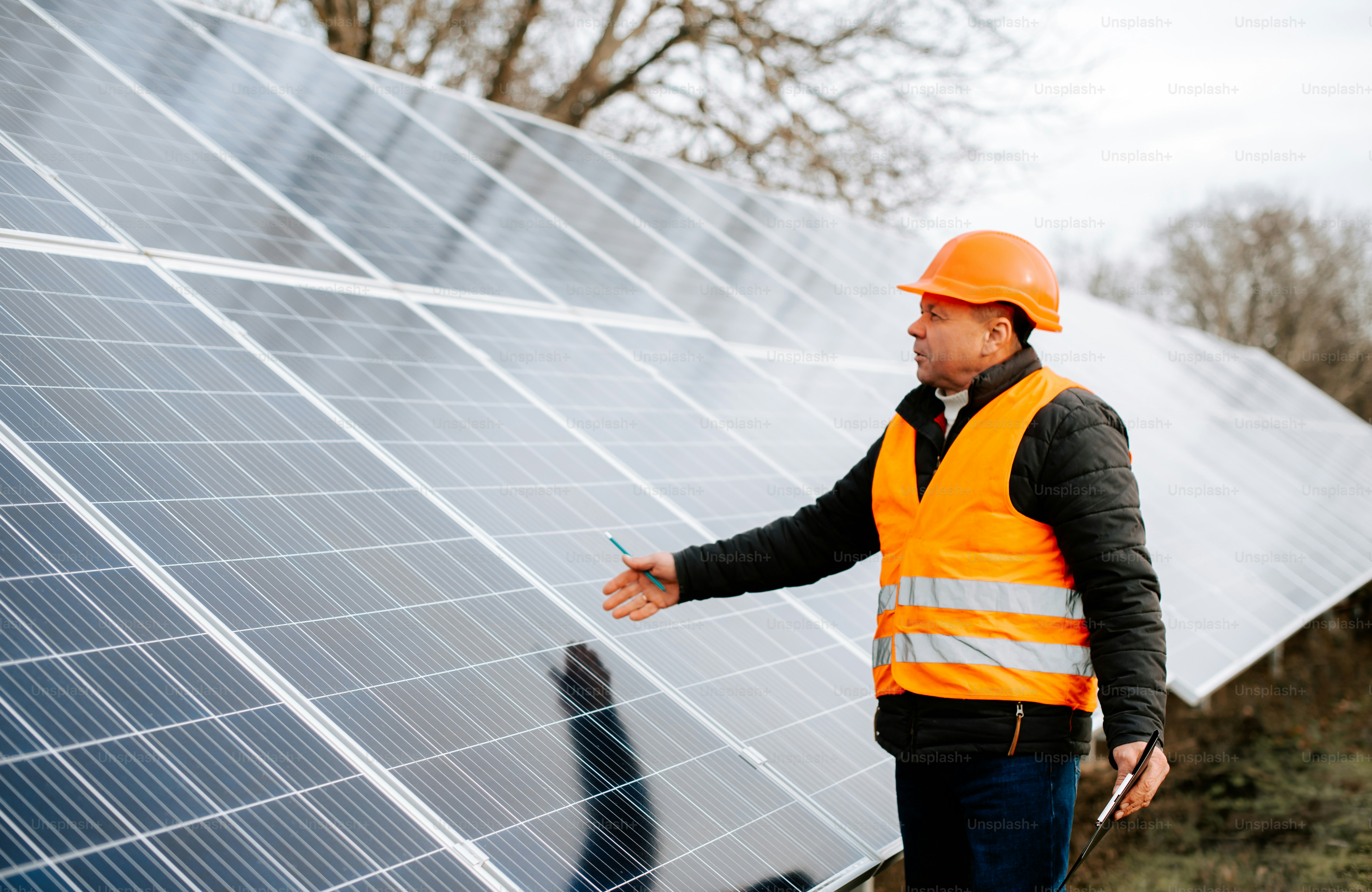A man standing next to a solar panel photo – Photovoltaic panels Image ...