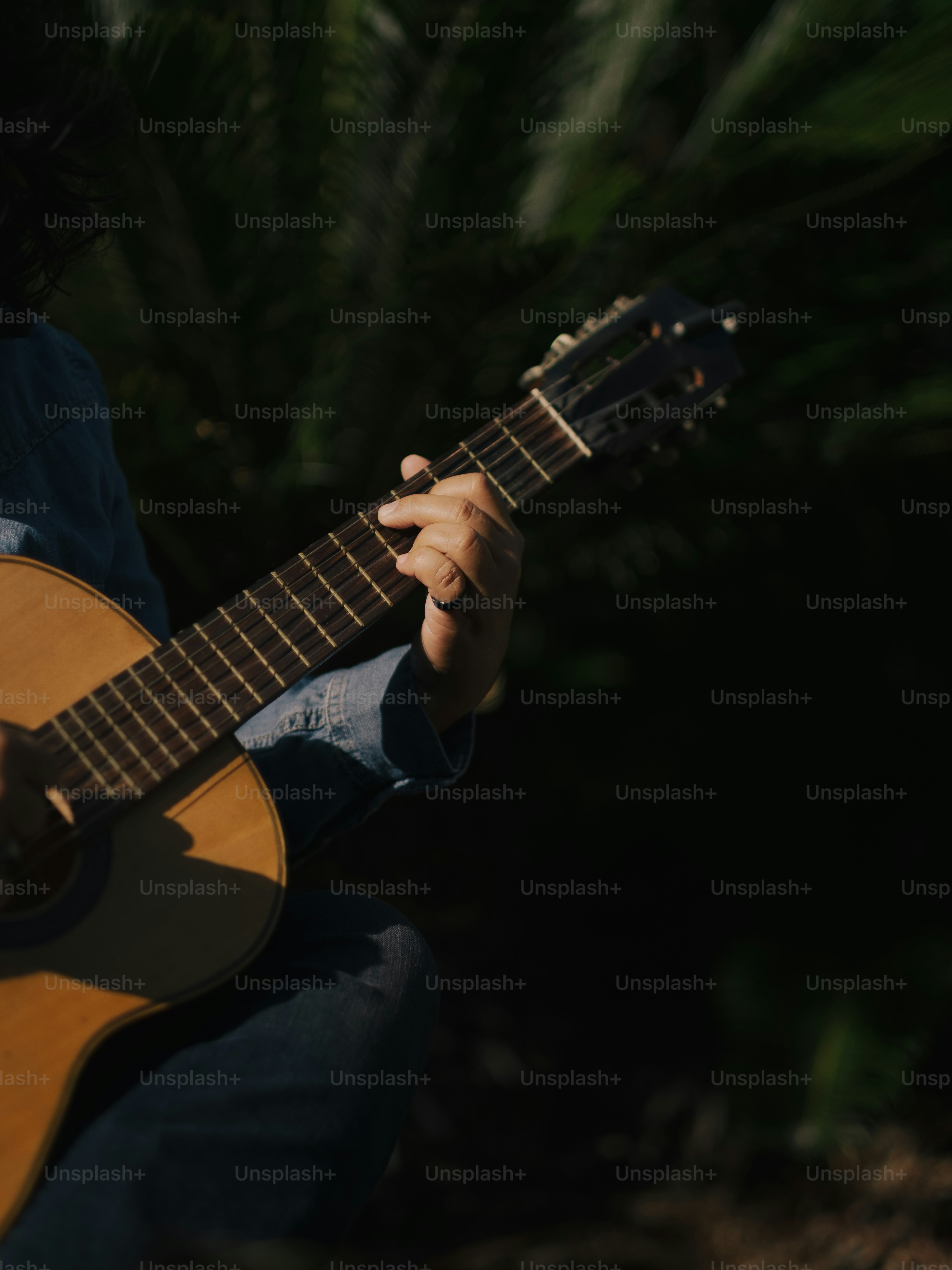 Foto Una persona sentada tocando una guitarra – Los Angeles Imagen en ...